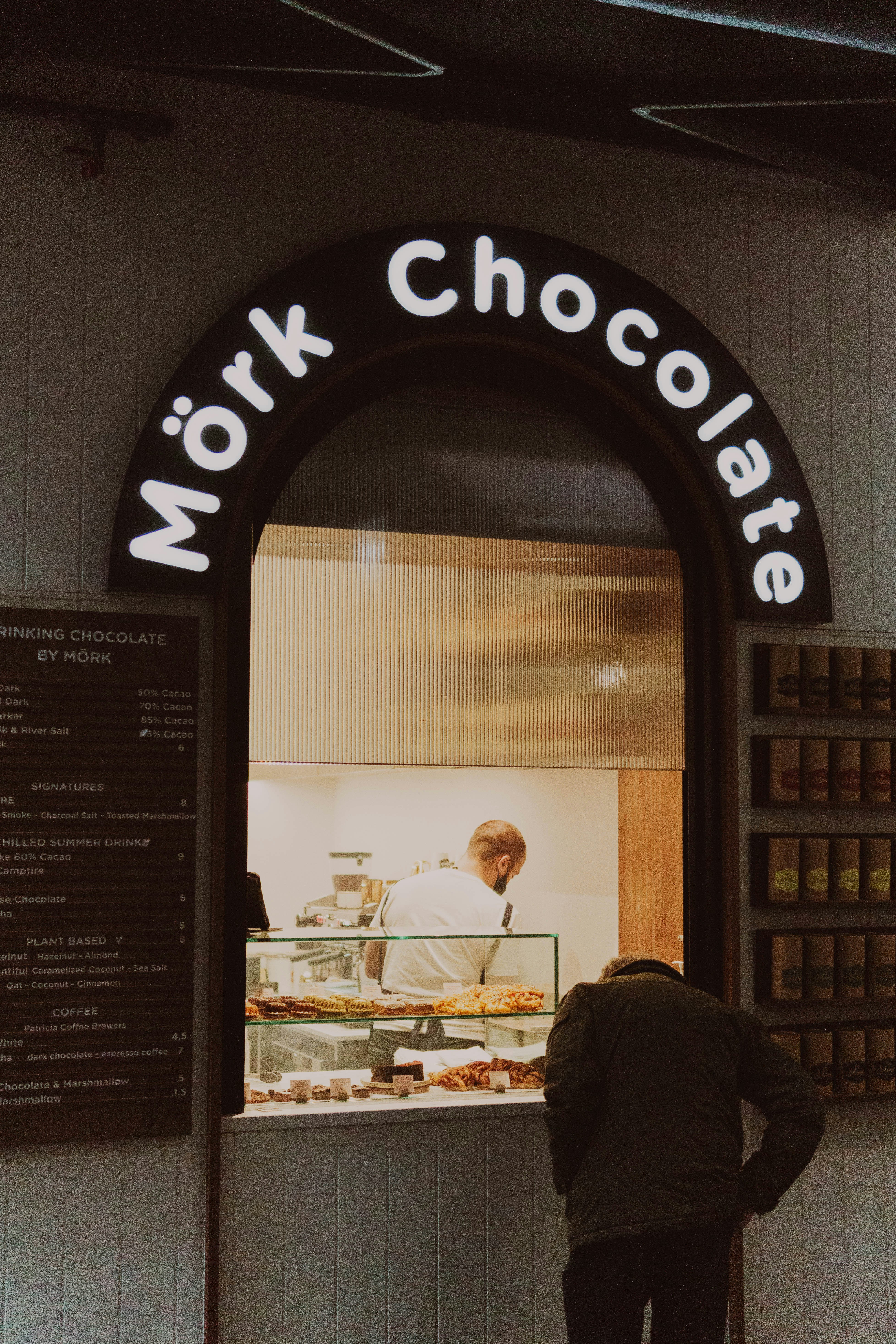 Under the Mörk Chocolate Arch: Quiet Focus at a Warm Counter Scene