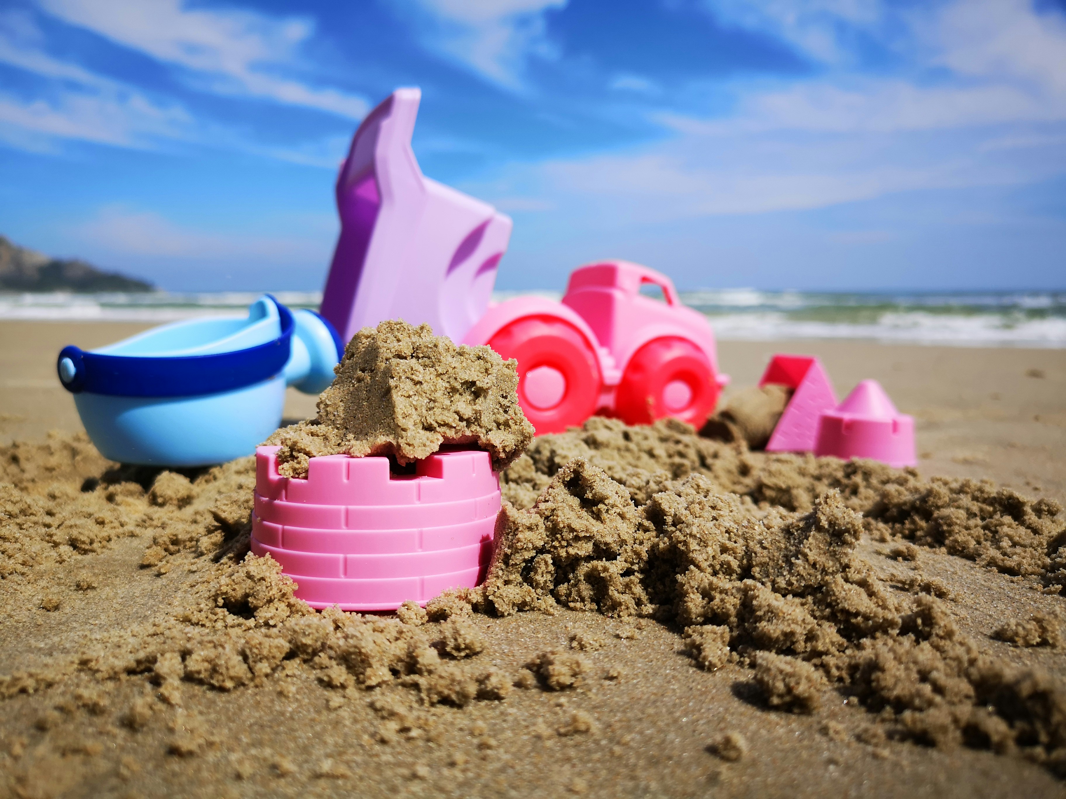 Colorful beach toys scattered in the sand, inviting a day of fun and creativity by the ocean. Perfect for a sunny day of play.