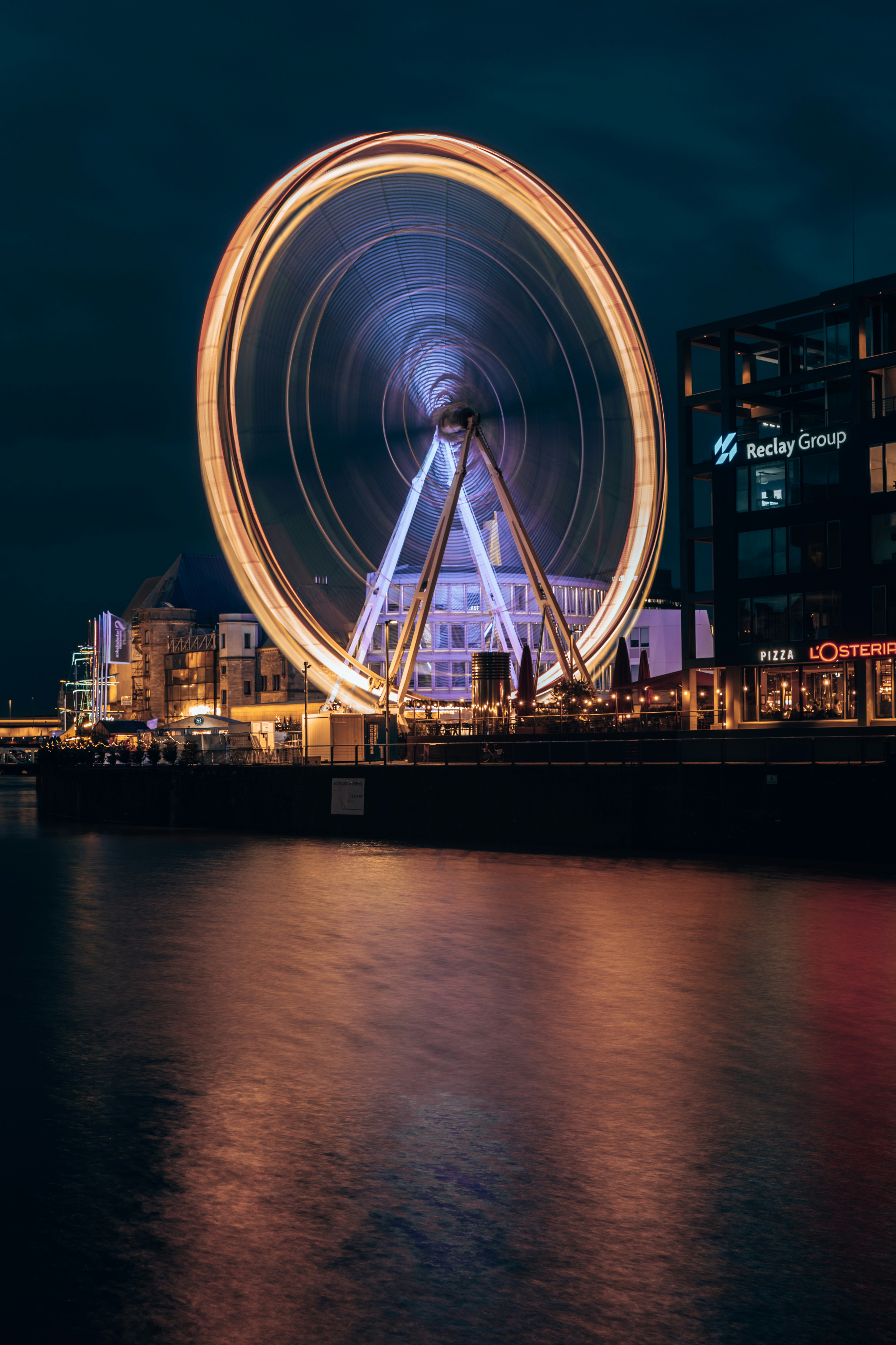 Neon Ring Over the Waterfront: A Night Ferris Wheel in Motion