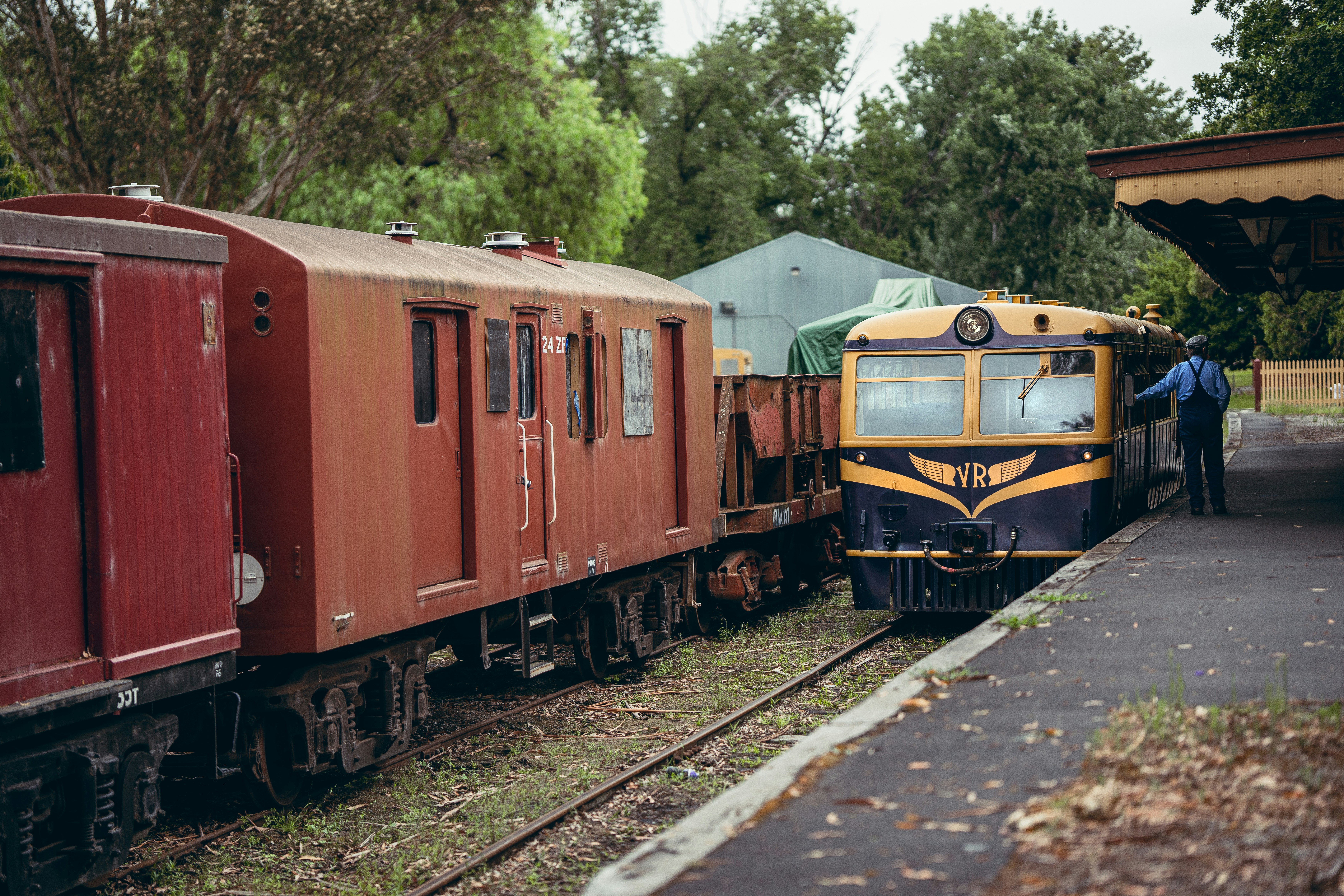 a man standing next to a train on a train track photo – Free Train ...