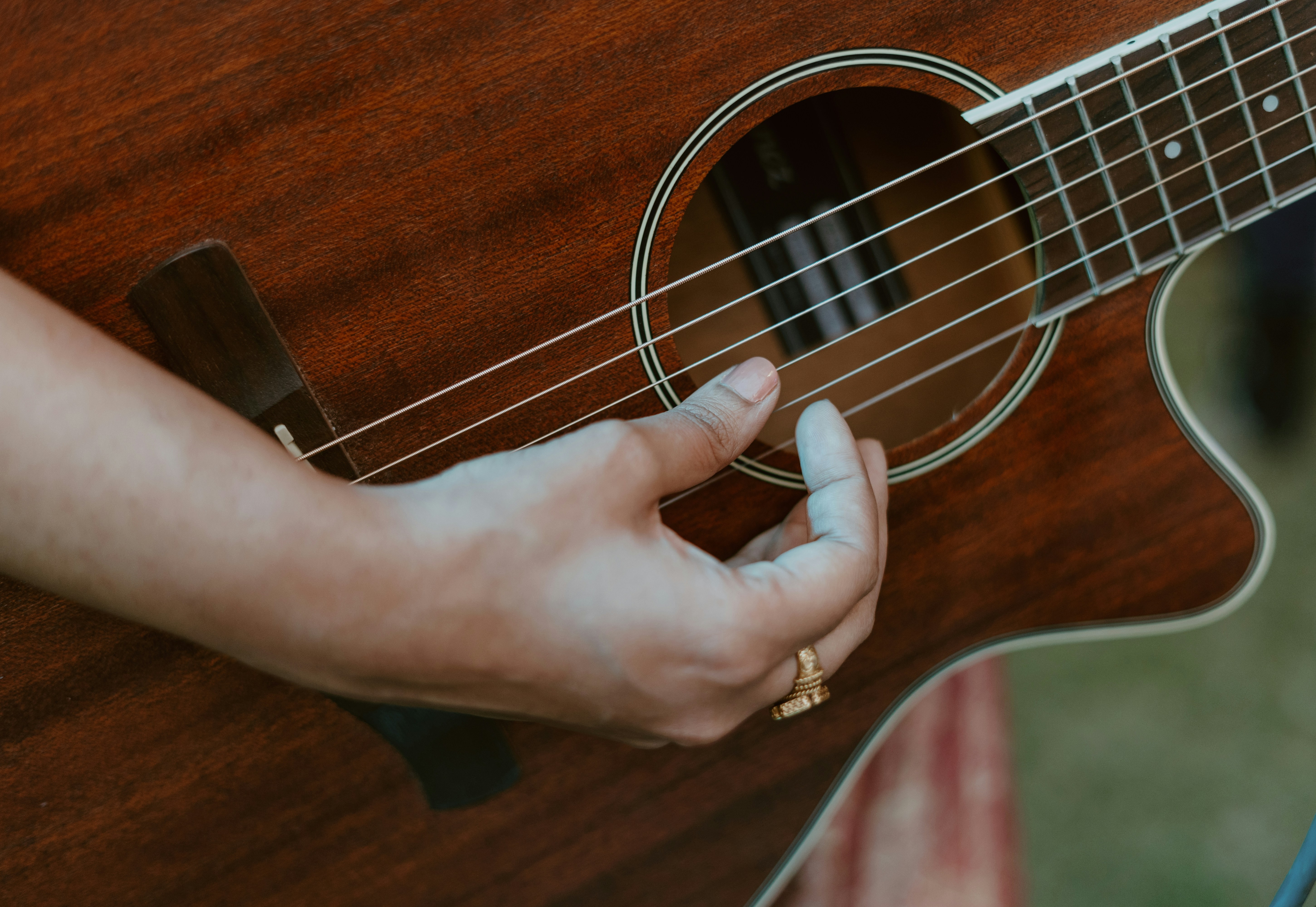 Close-up of a hand playing an acoustic guitar, highlighting the intricate details of the instrument and the musician's engagement. 
