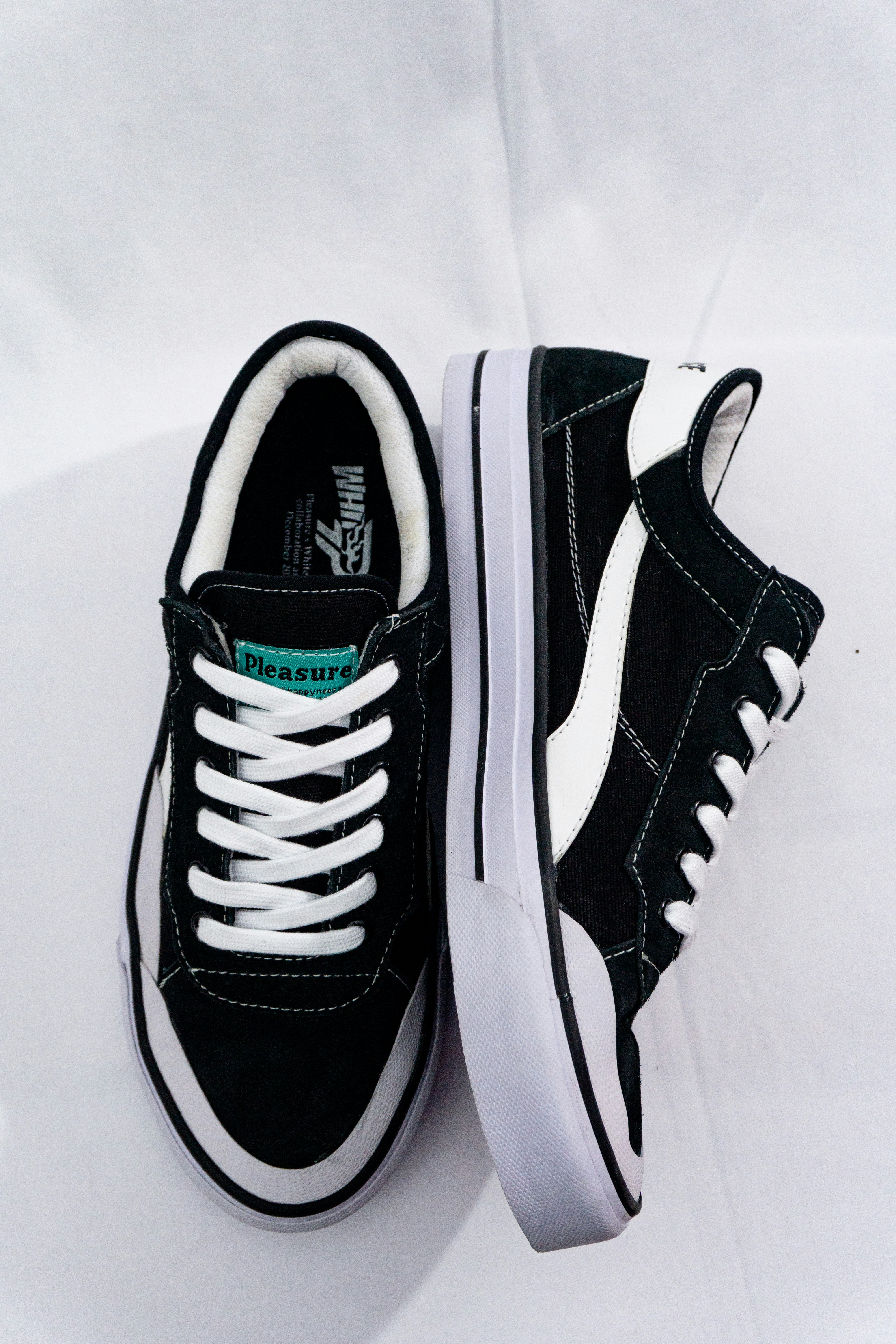 Black and white sneakers with a retro design, featuring prominent laces and branding. Perfectly styled for casual wear.