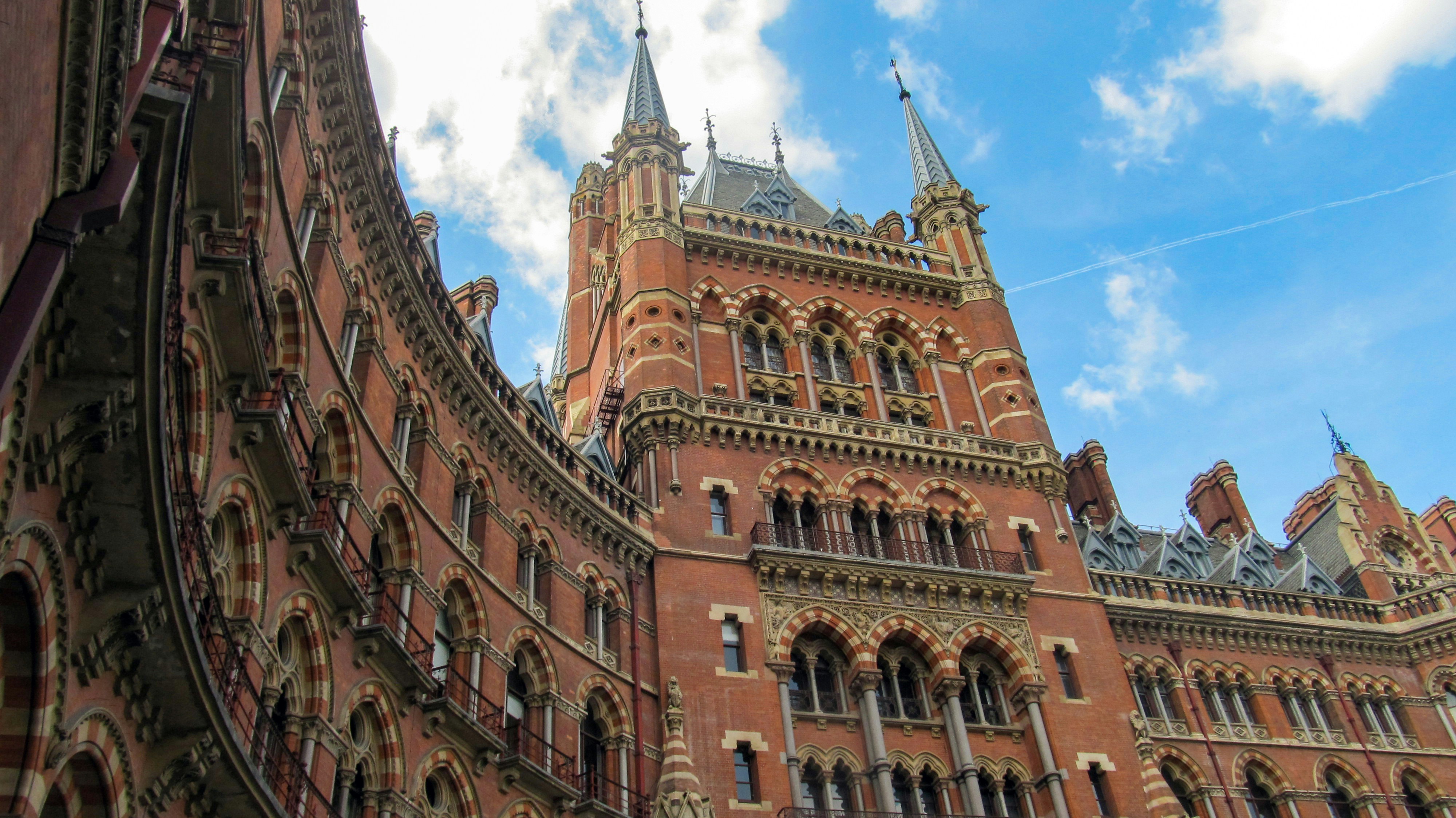 Intricate brickwork and towering spires of a historic Victorian building against a clear blue sky.