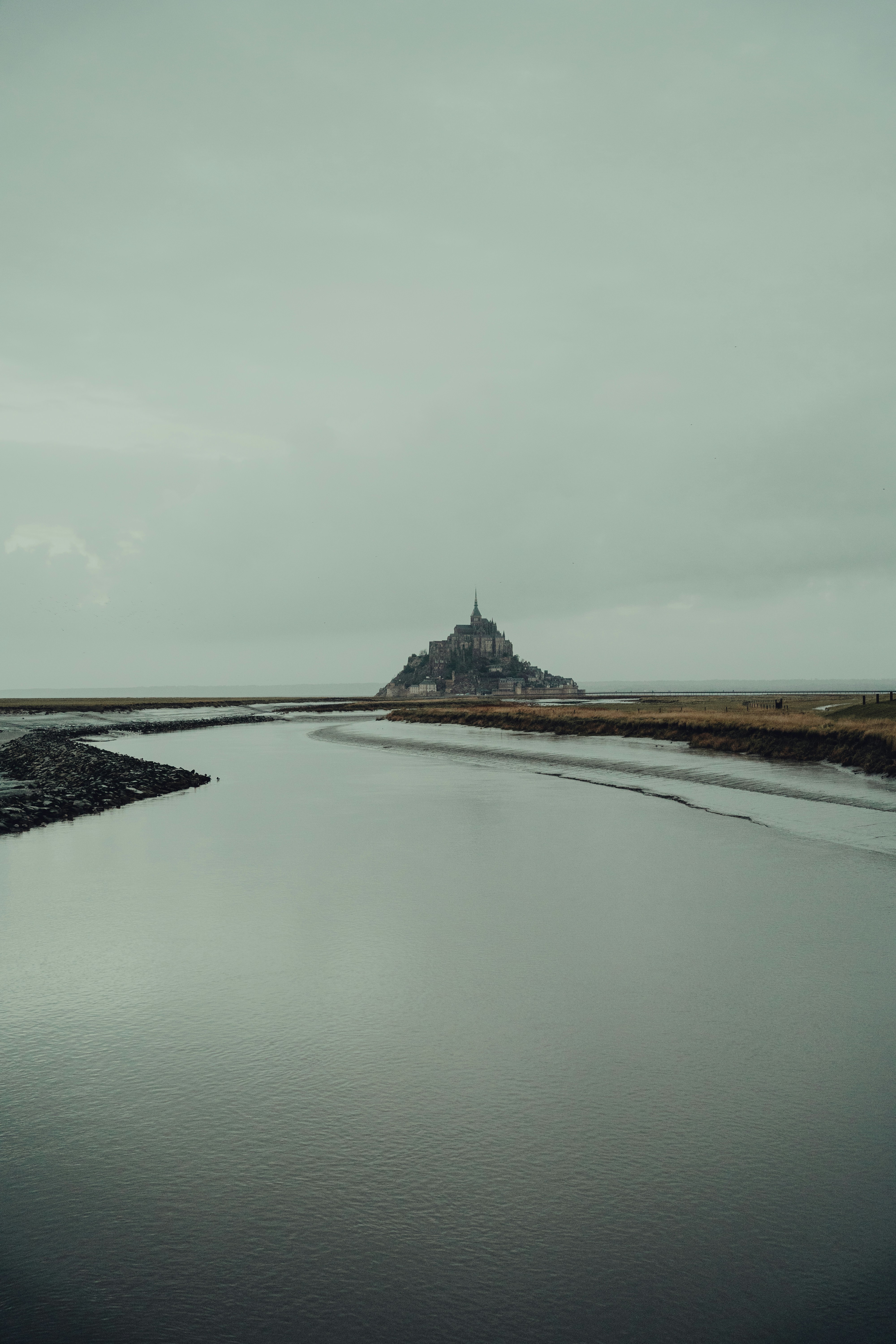 Foto Una gran masa de agua con un castillo al fondo – Imagen Mont Saint ...