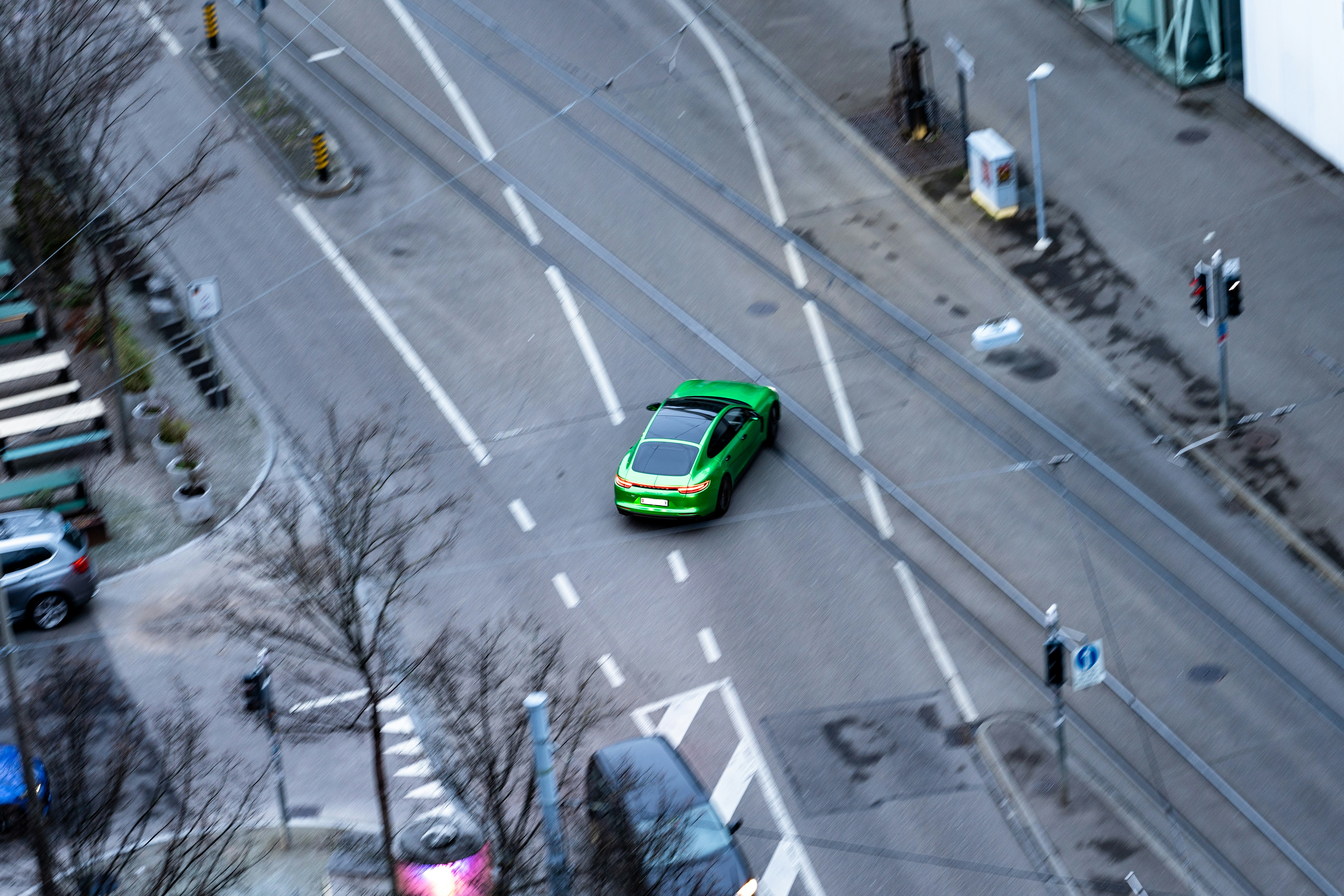 A green car driving down a street next to a traffic light photo – Free ...
