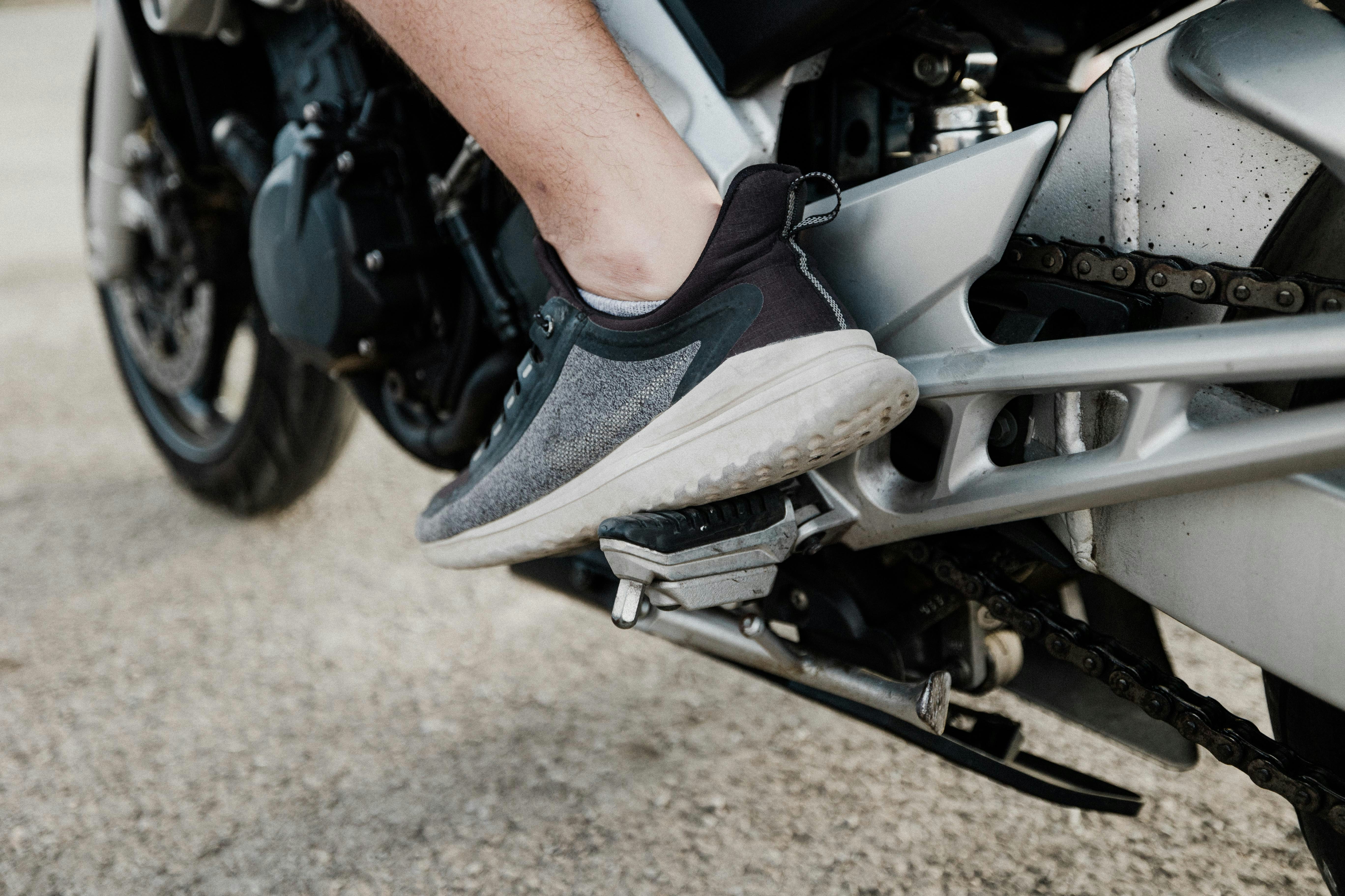 Footstep on the Verge: A Rider's Sneaker Resting on the Bike's Footpeg