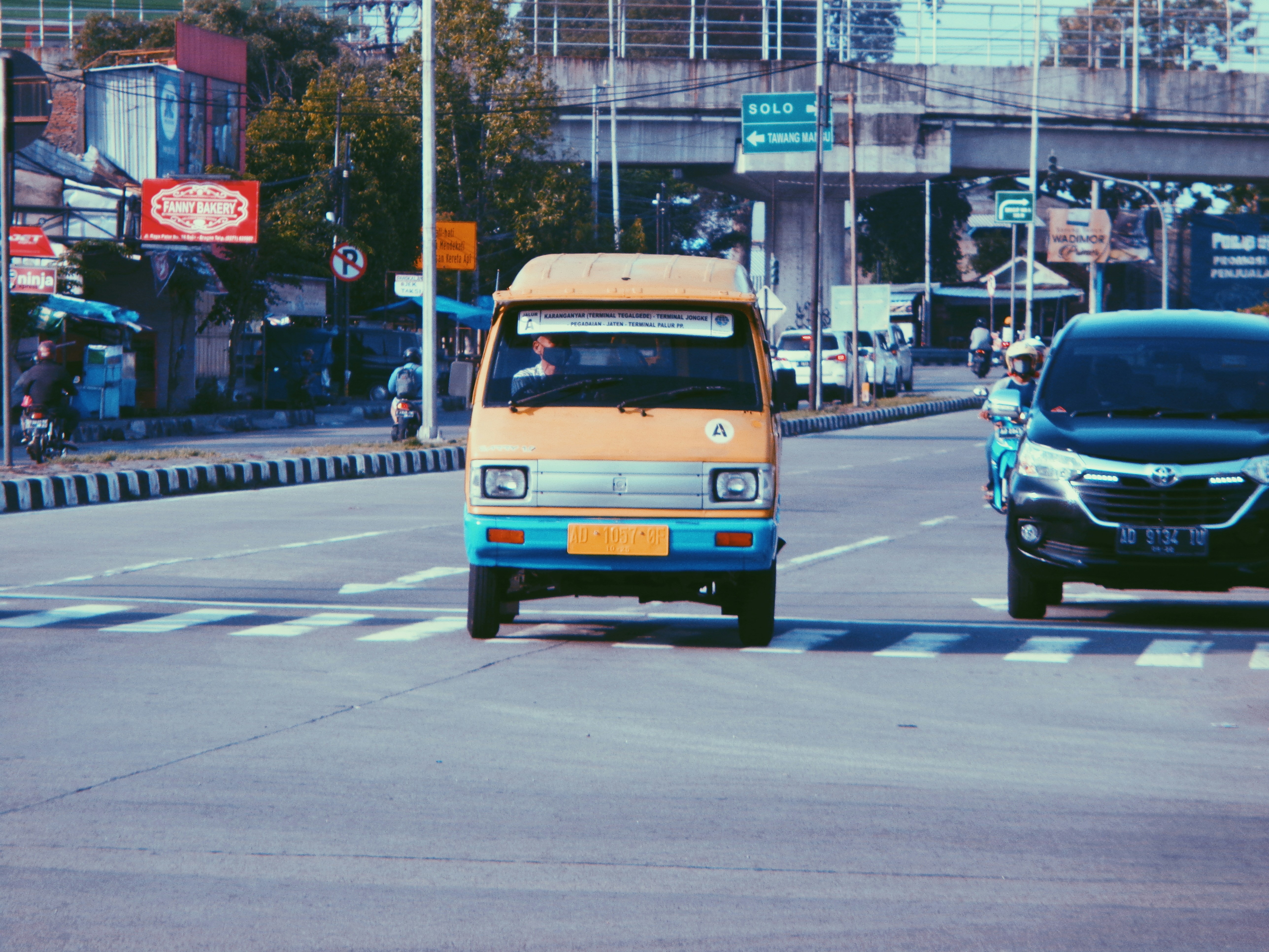 Colorful transport vehicle navigating through busy city streets, showcasing urban life and movement.