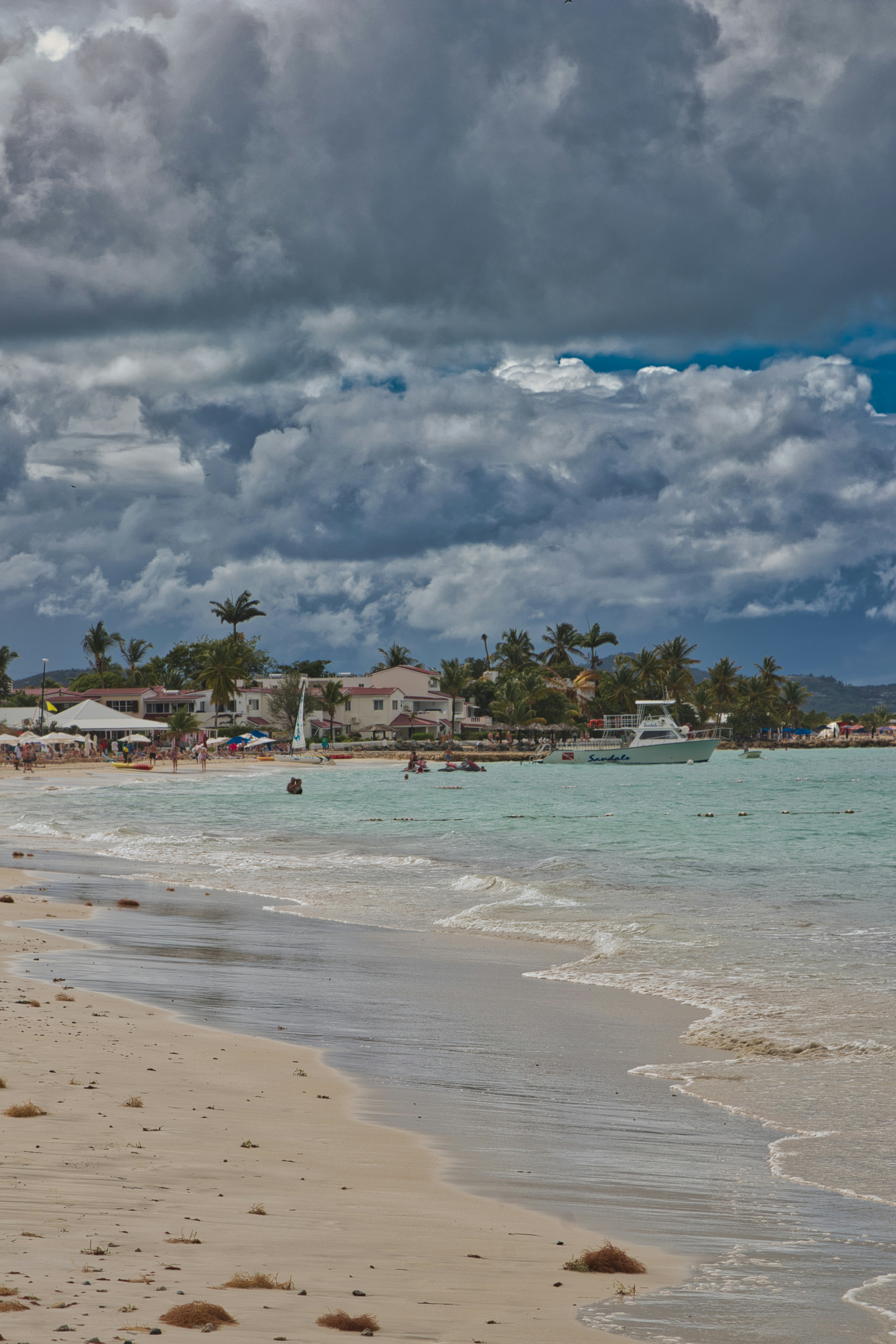 Anchored Boat Along a Turquoise Shore Under a Dramatic Caribbean Sky
