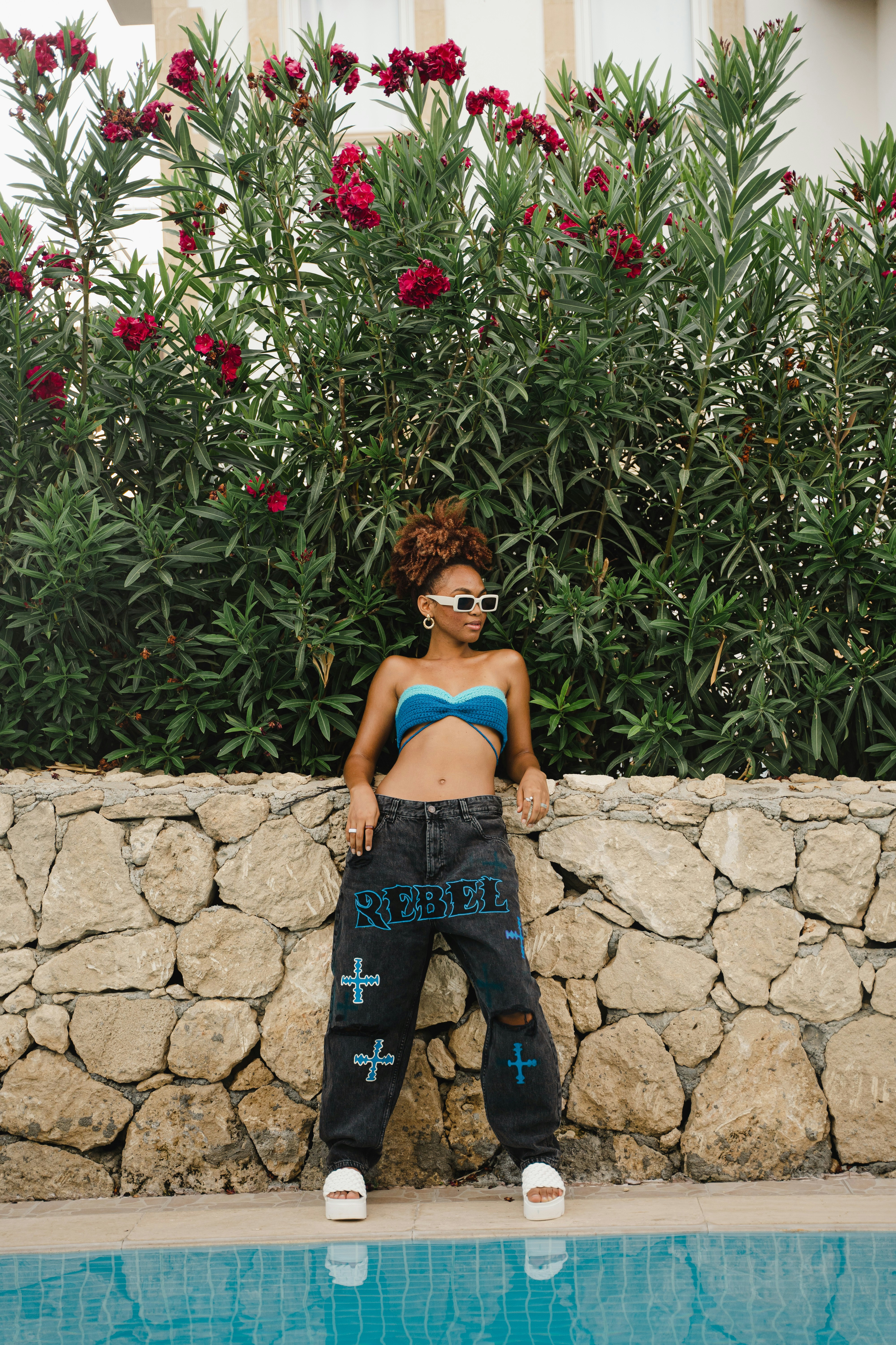 Poolside Rebel: Blue Bandeau, Bold Denim, and a Coral Backdrop