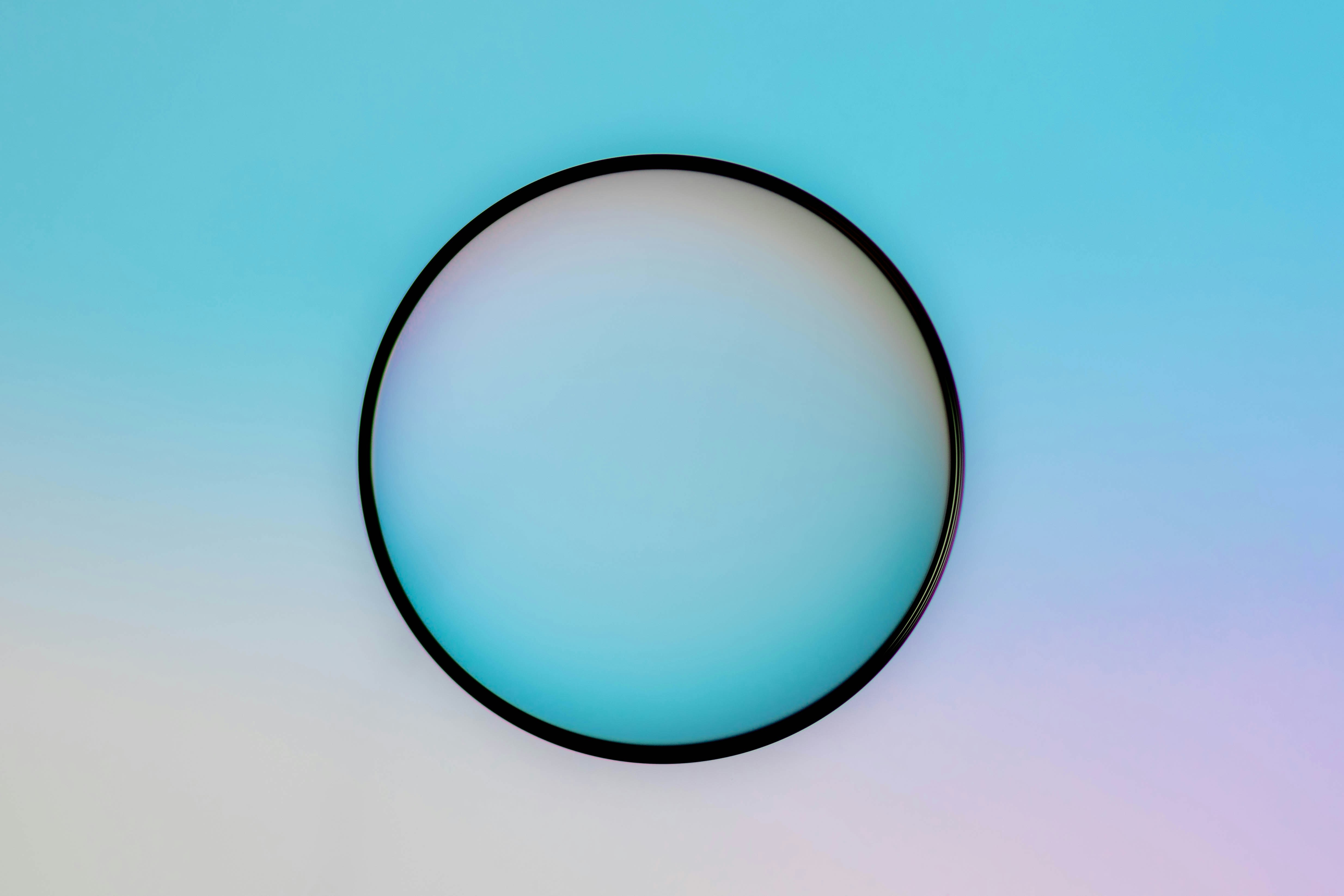 A minimalist design featuring a circular shape against a gradient background of soft blue and purple hues.