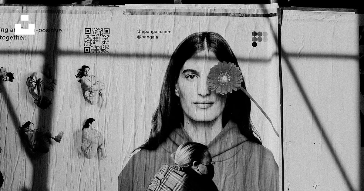 Foto Una Foto En Blanco Y Negro De Una Mujer Parada Frente A Un Cartel