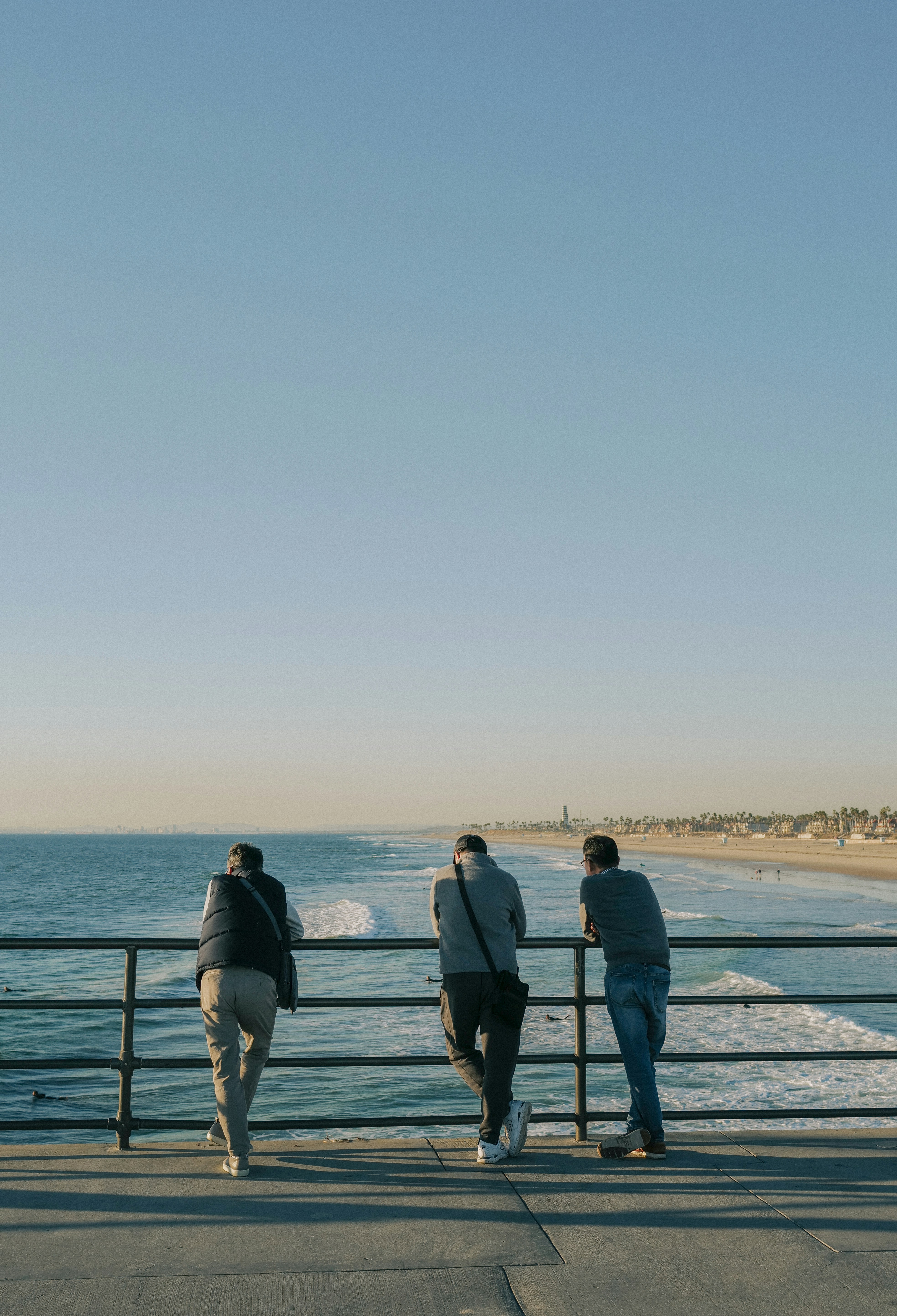 Seaside Gaze: Trio at the Pier Over the Quiet Atlantic