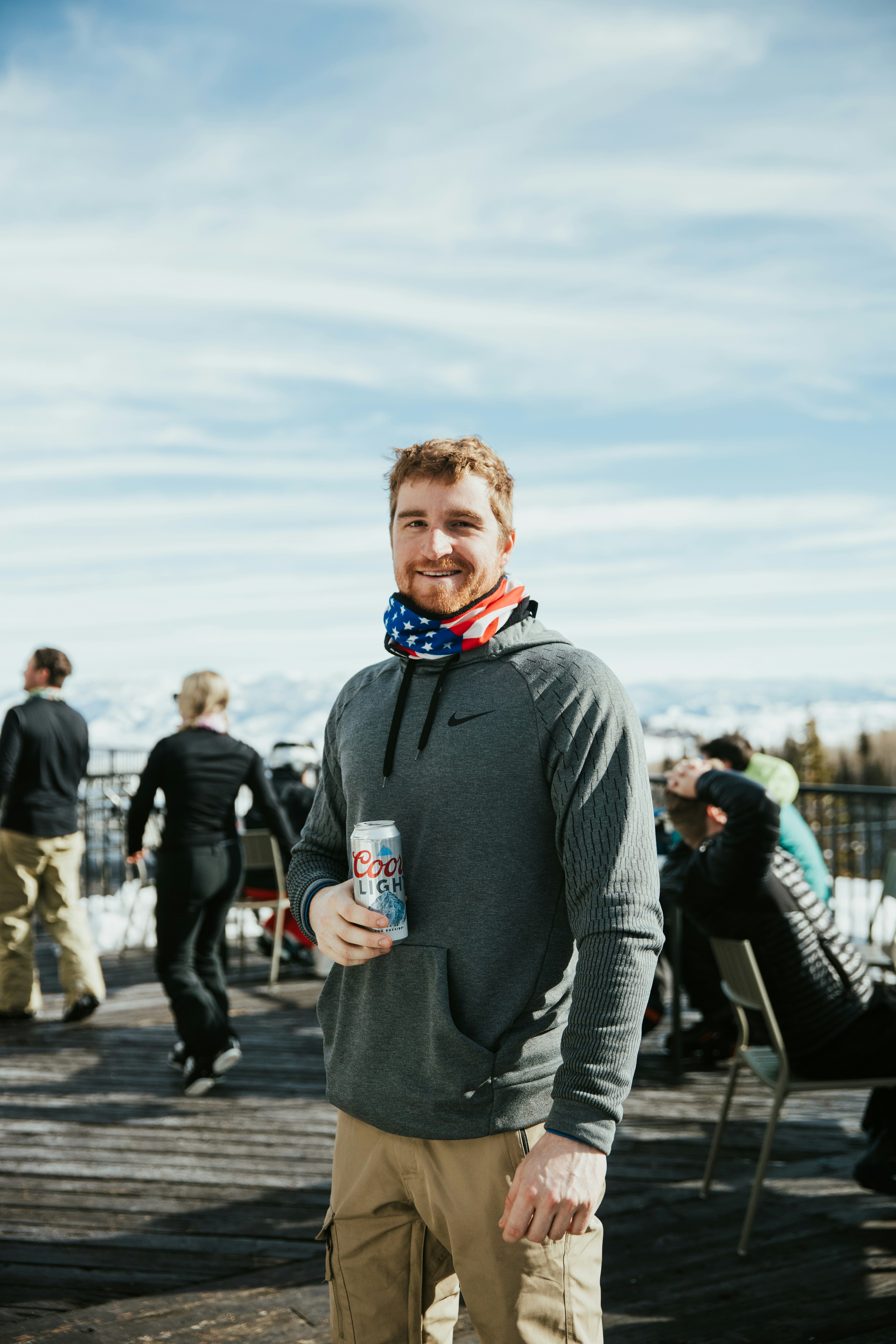 Snowy Deckside Cheer: A Bearded Man with American Bandana Holding a Coors Light