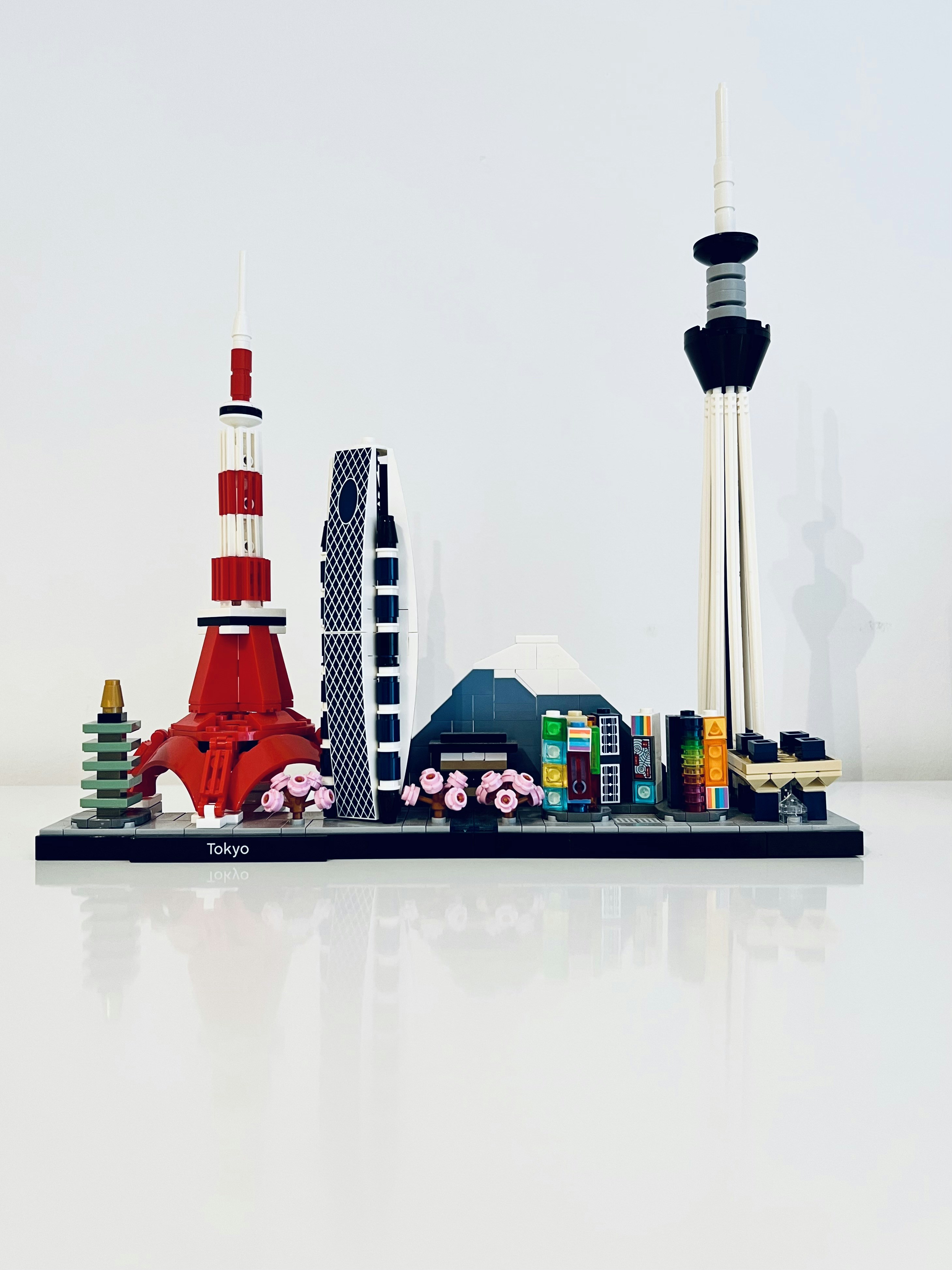 Detailed LEGO representation of Tokyo's skyline featuring iconic structures like Tokyo Tower and Skytree, adorned with cherry blossoms. The scene captures the essence of the city.