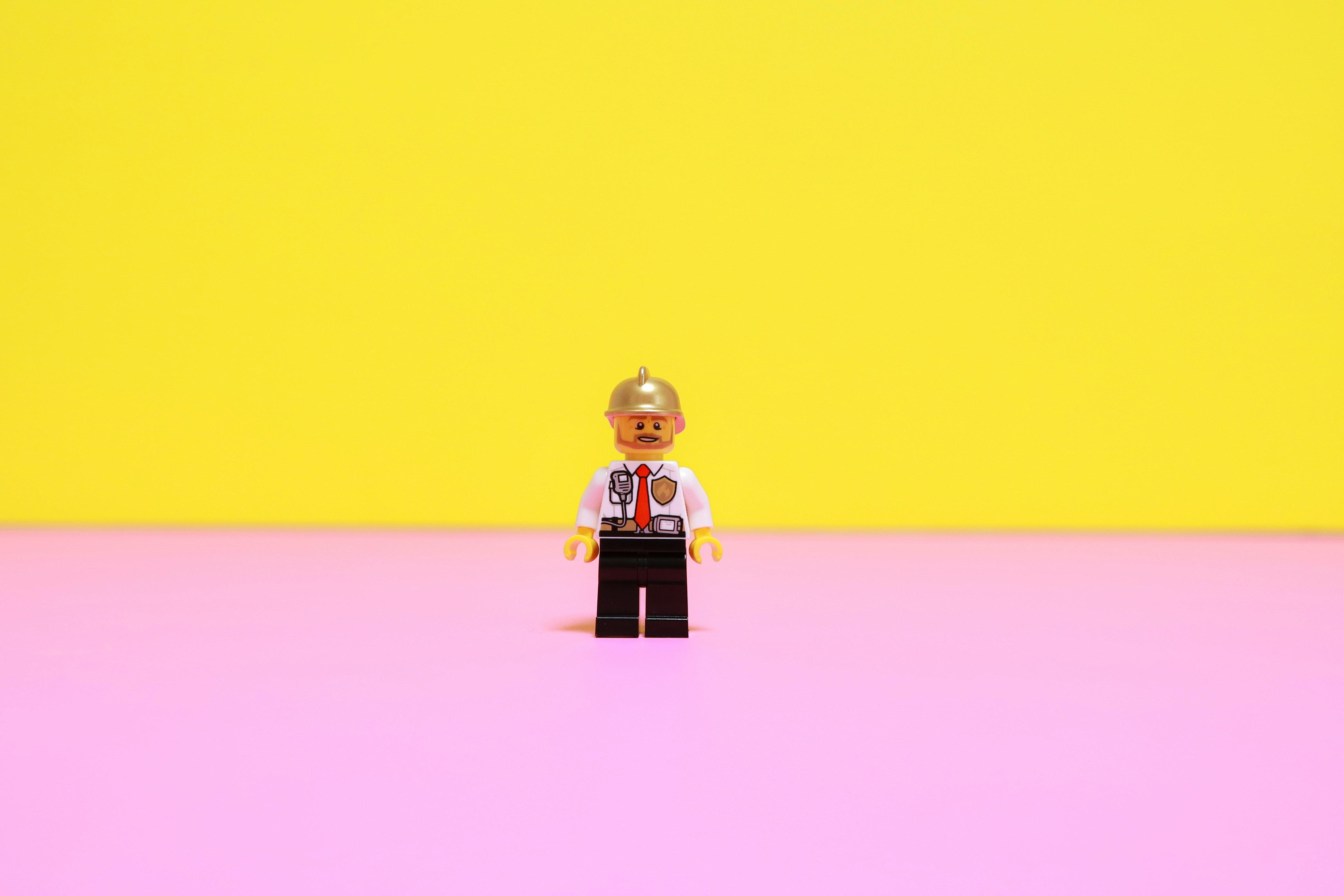 a lego man standing in front of a yellow and pink background