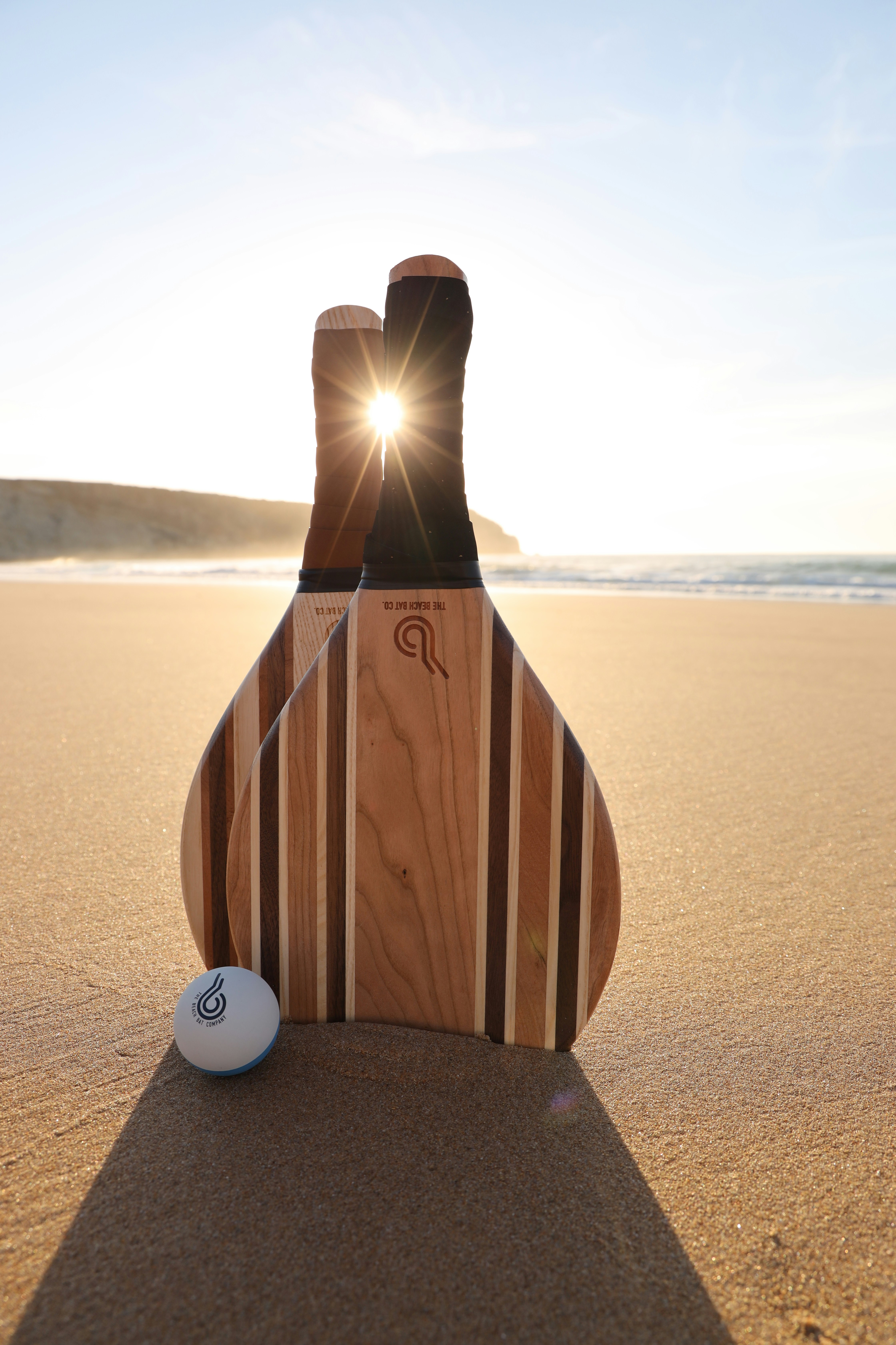 Sunlit Paddleboard: Vertical Stakes and a Ball on the Shore