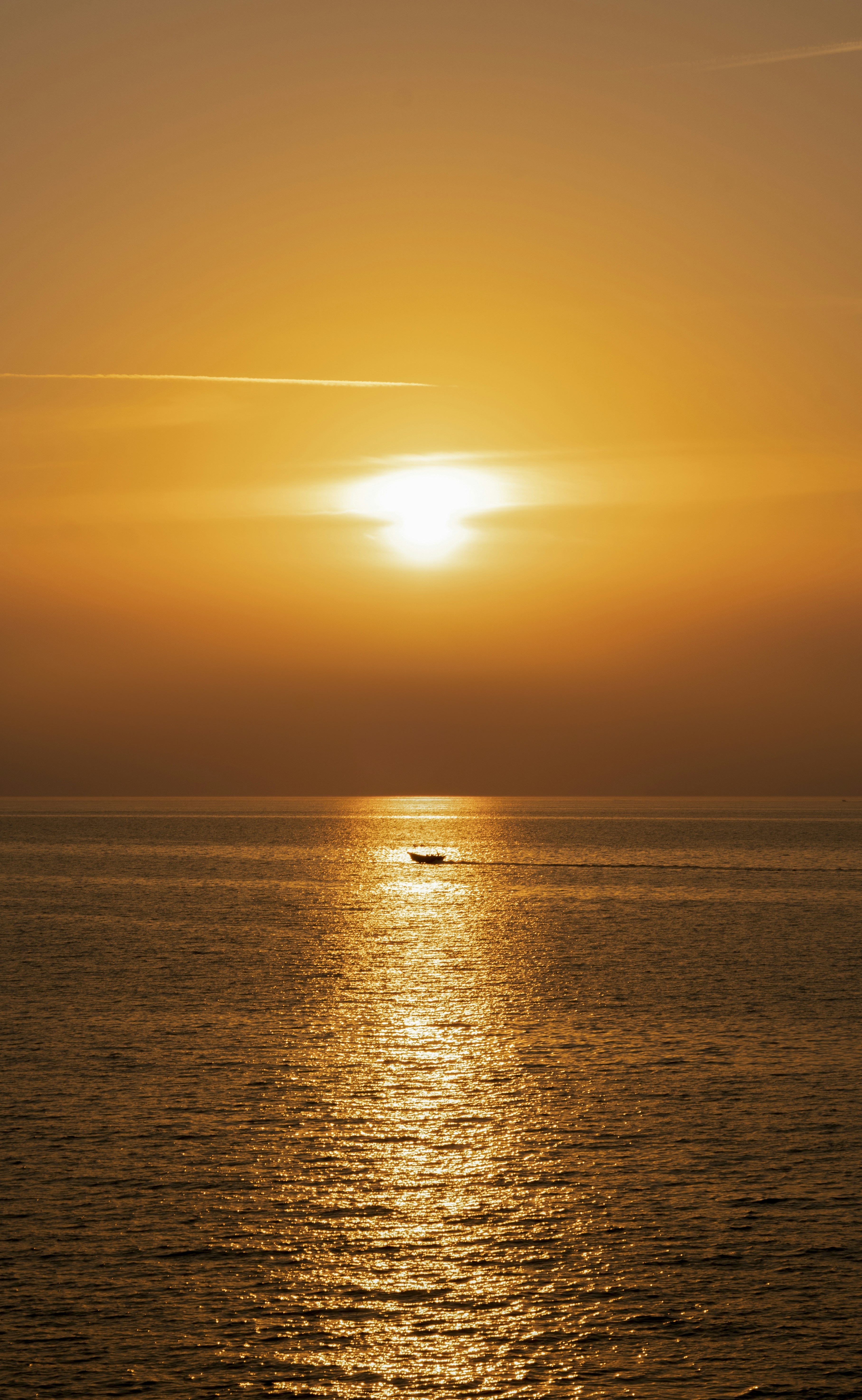 The sun is setting over the ocean with a boat in the water photo – Free ...