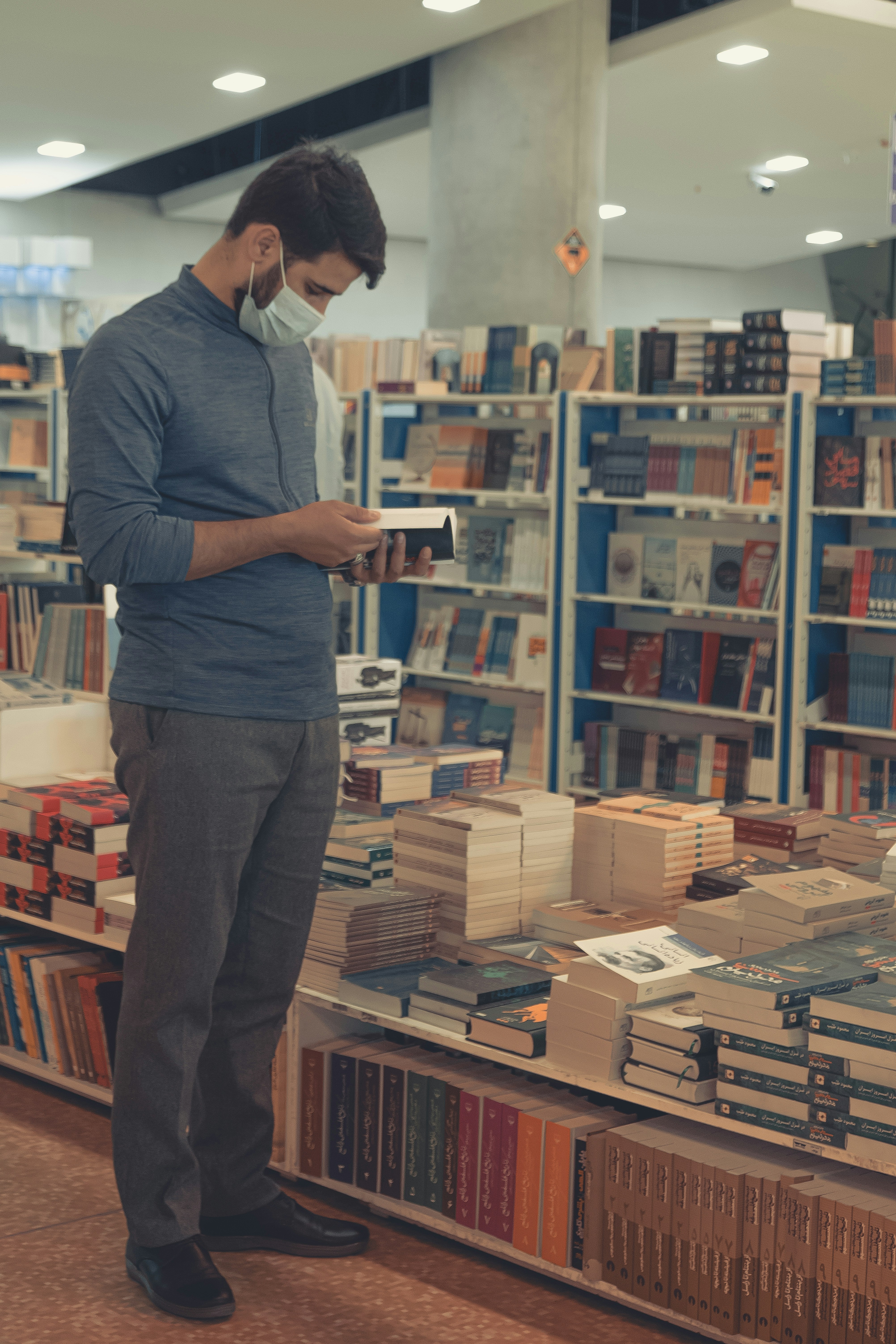 Masked Reader in the Stacks: A Moment of Quiet Discovery