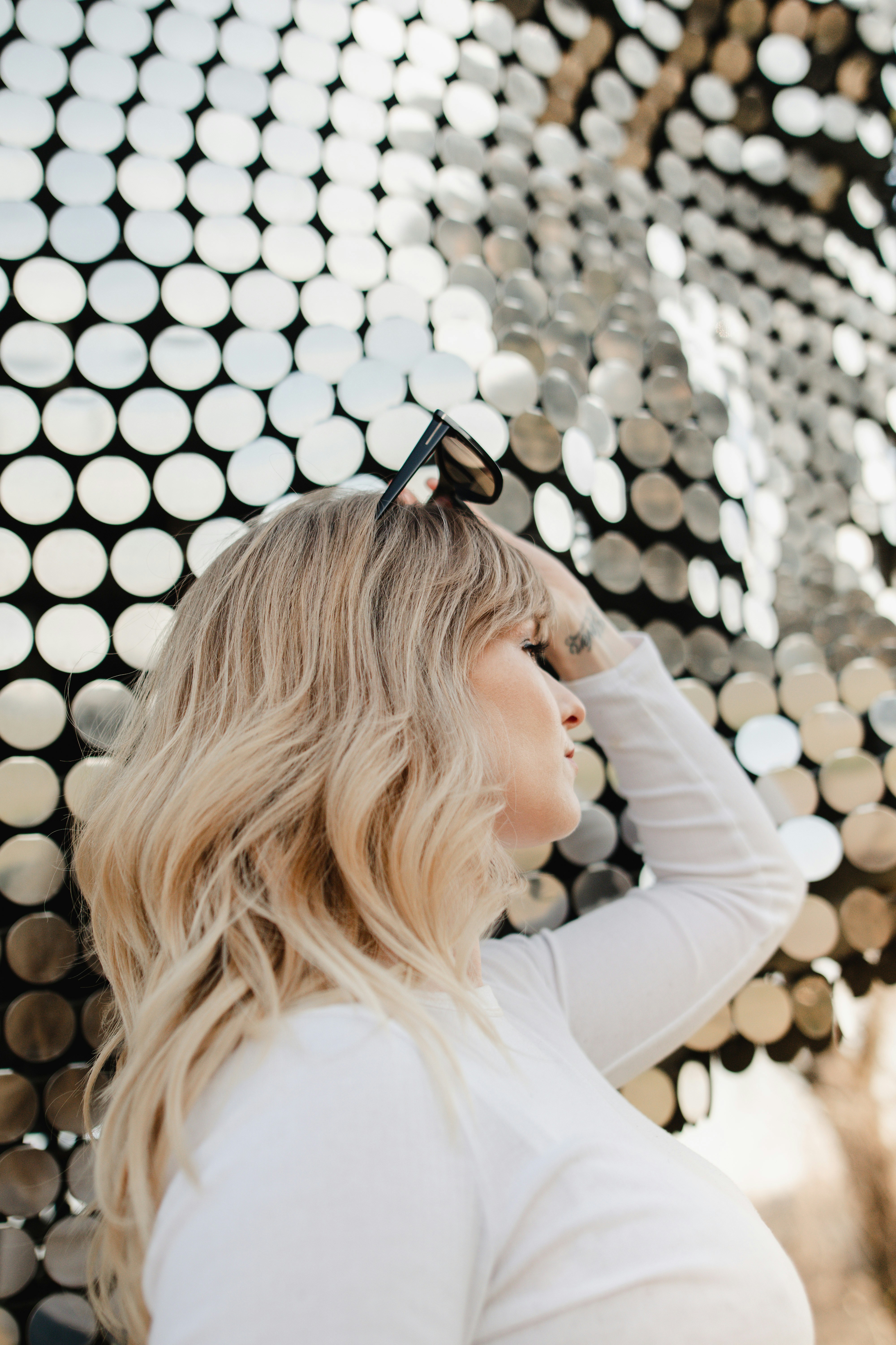 Blonde silhouette in front of a mirrored circle tapestry