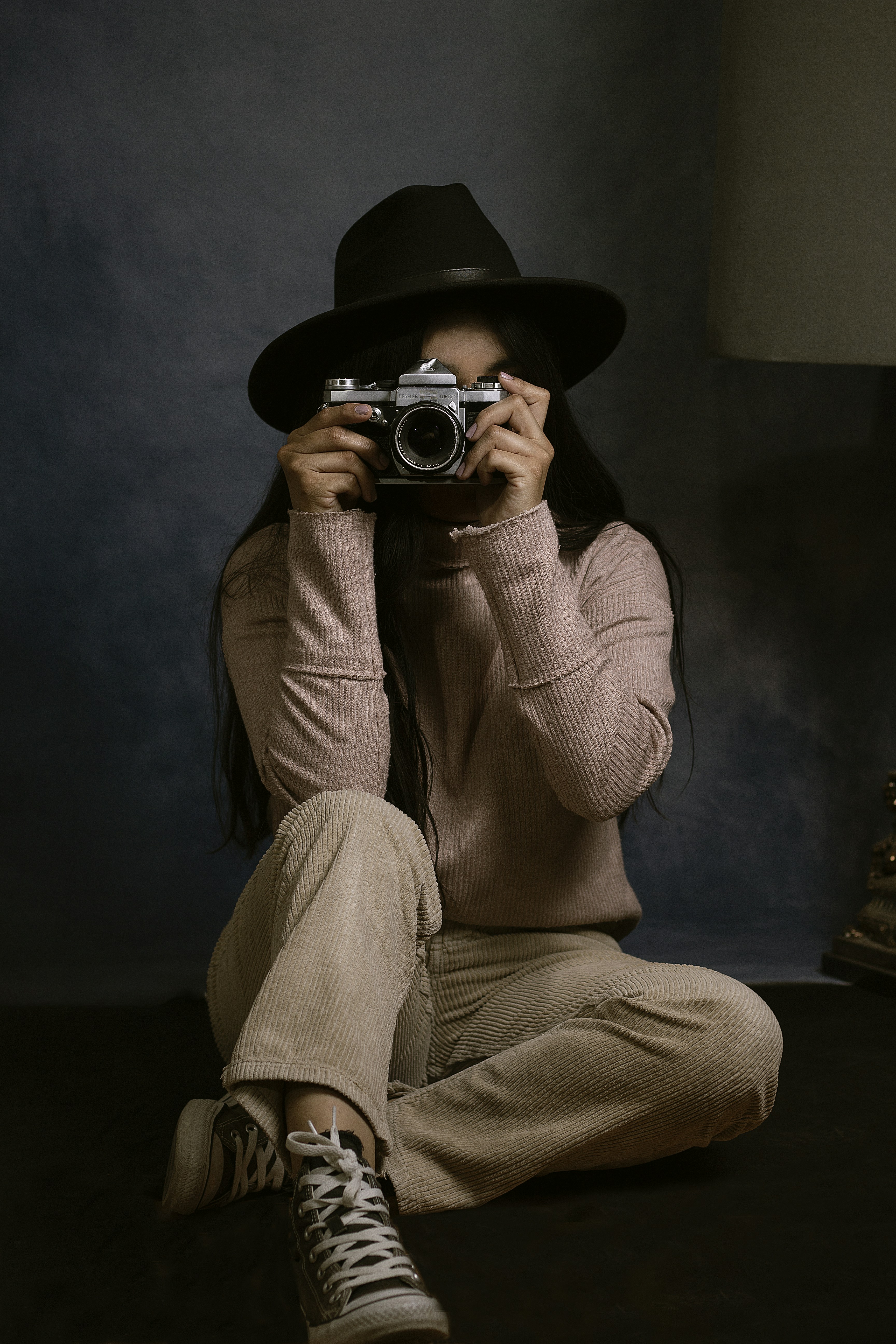 Quiet Focus in a Studio Moment: A Seated Photographer with a Vintage Silver Camera