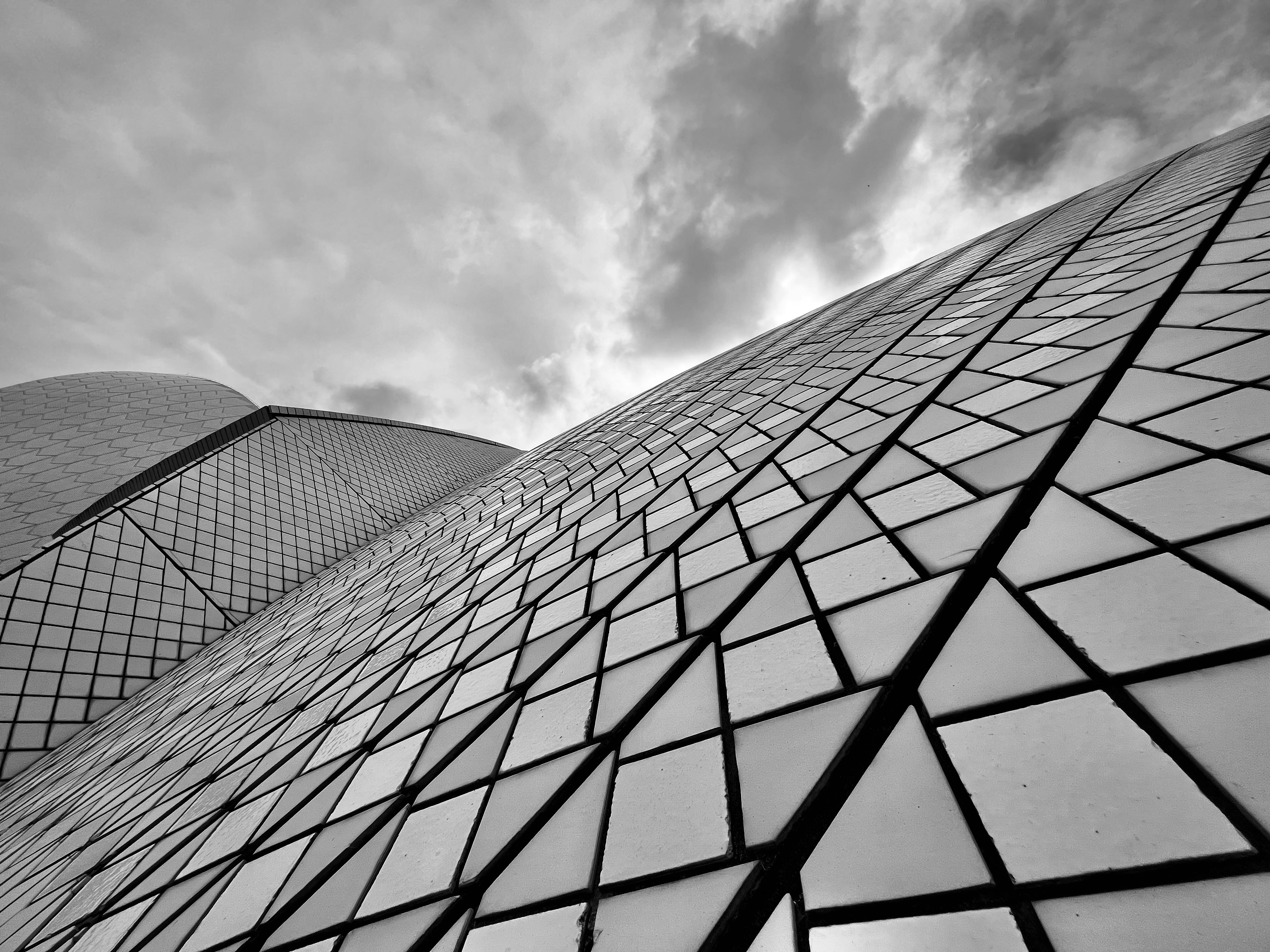 Close-up of geometric tile patterns on a curved architectural surface with a cloudy sky above.