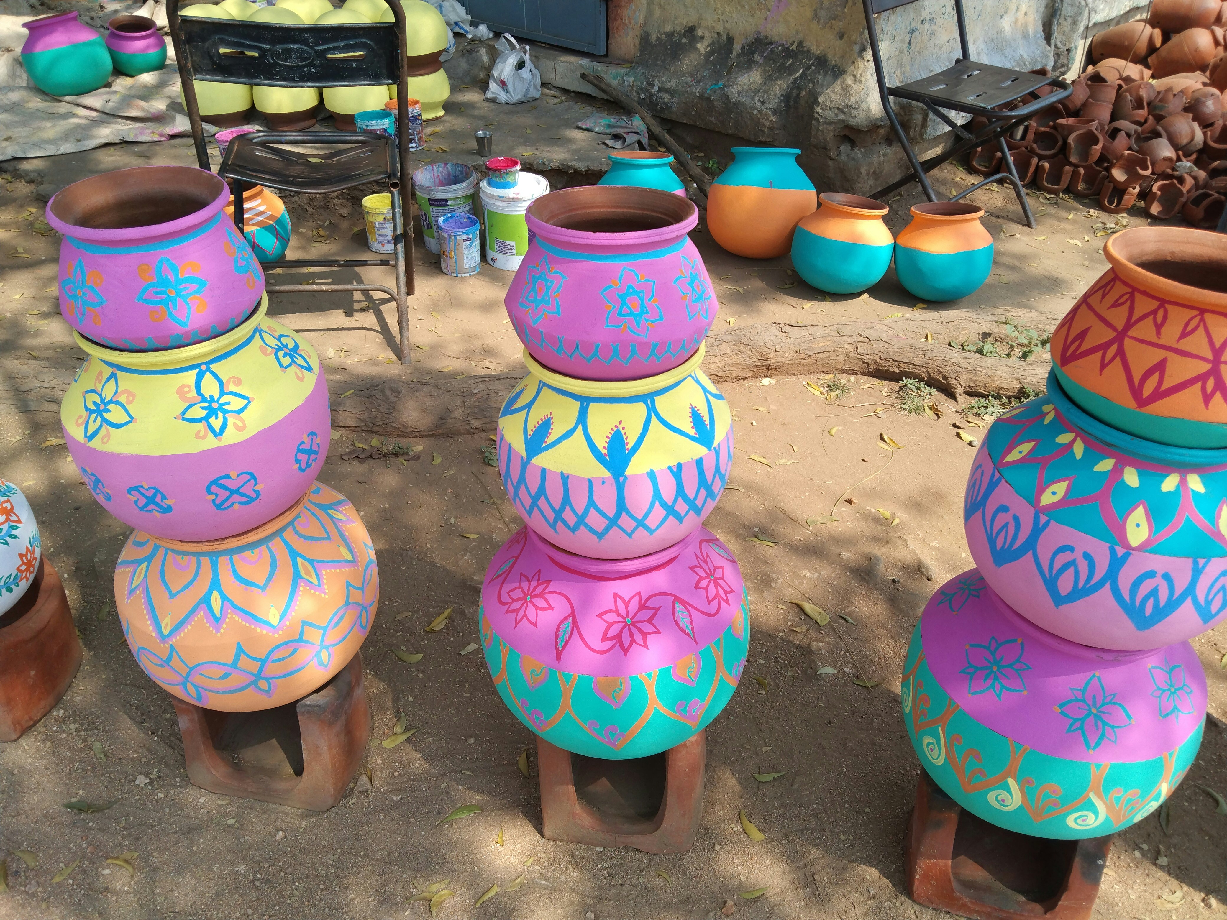 Vibrant Painted Pots: Stacked Ceramics Under Outdoor Workshop Light