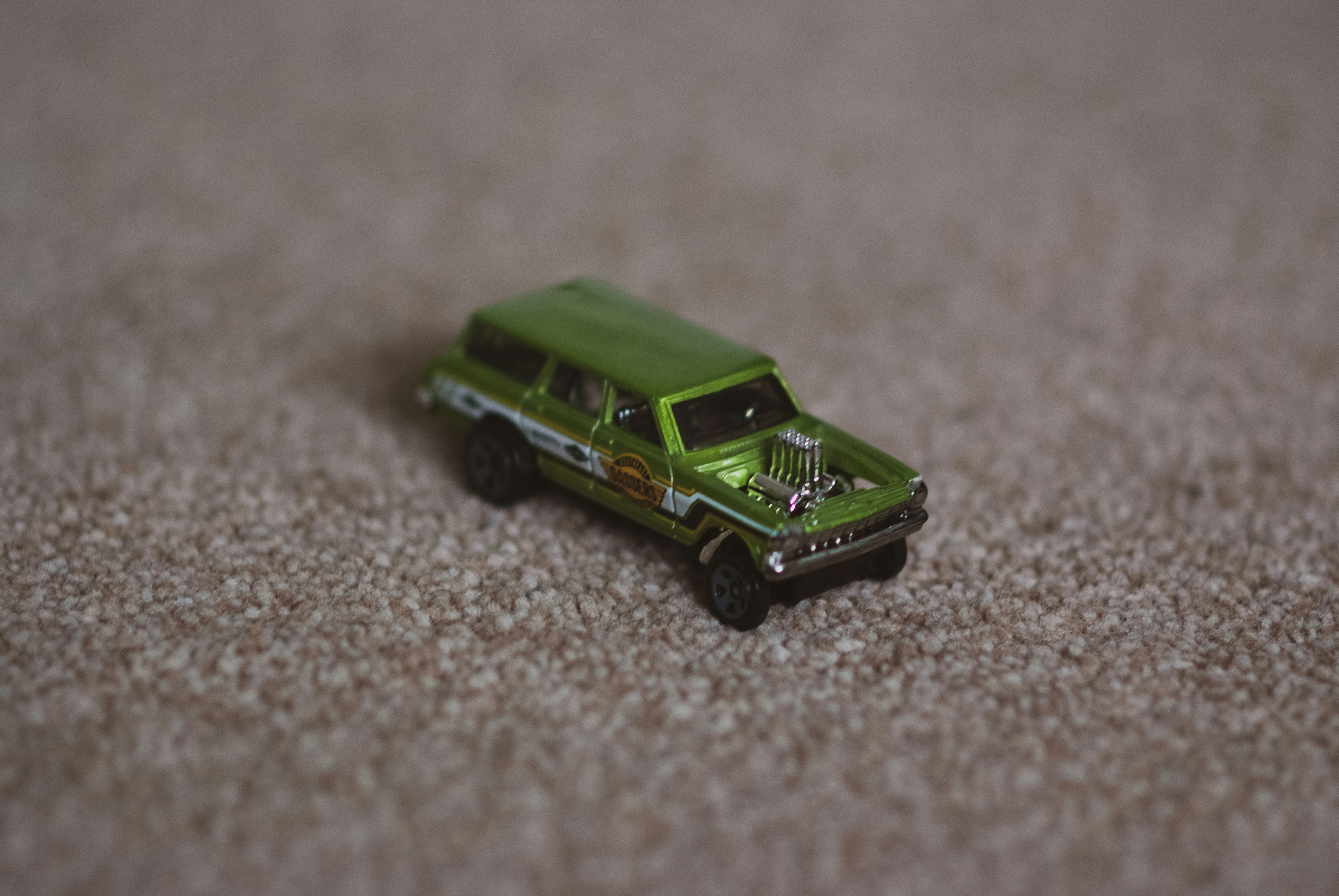 Green toy car resembling a Chevy Nova displayed on a textured surface.