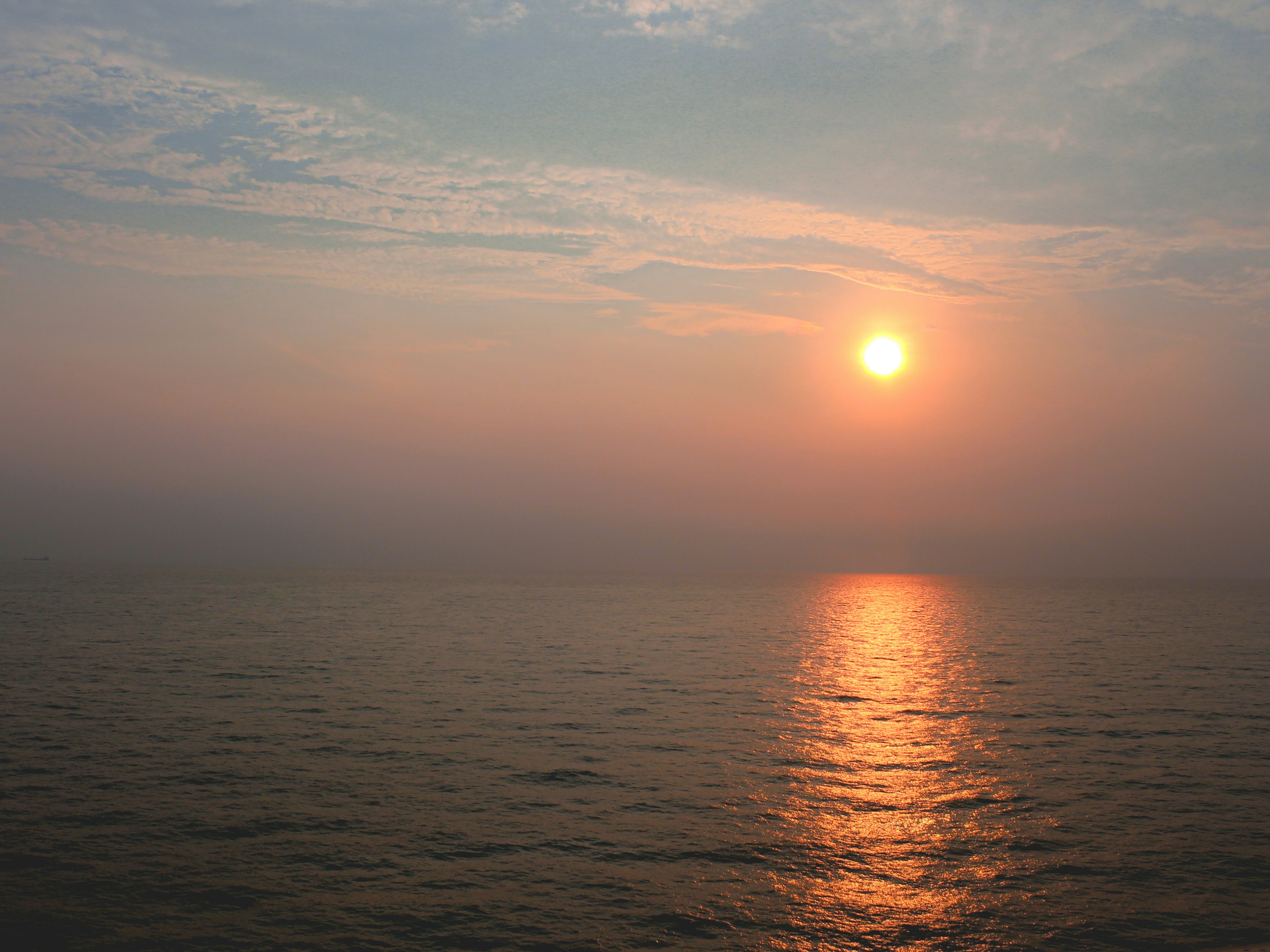 the sun is setting over the ocean on a cloudy day