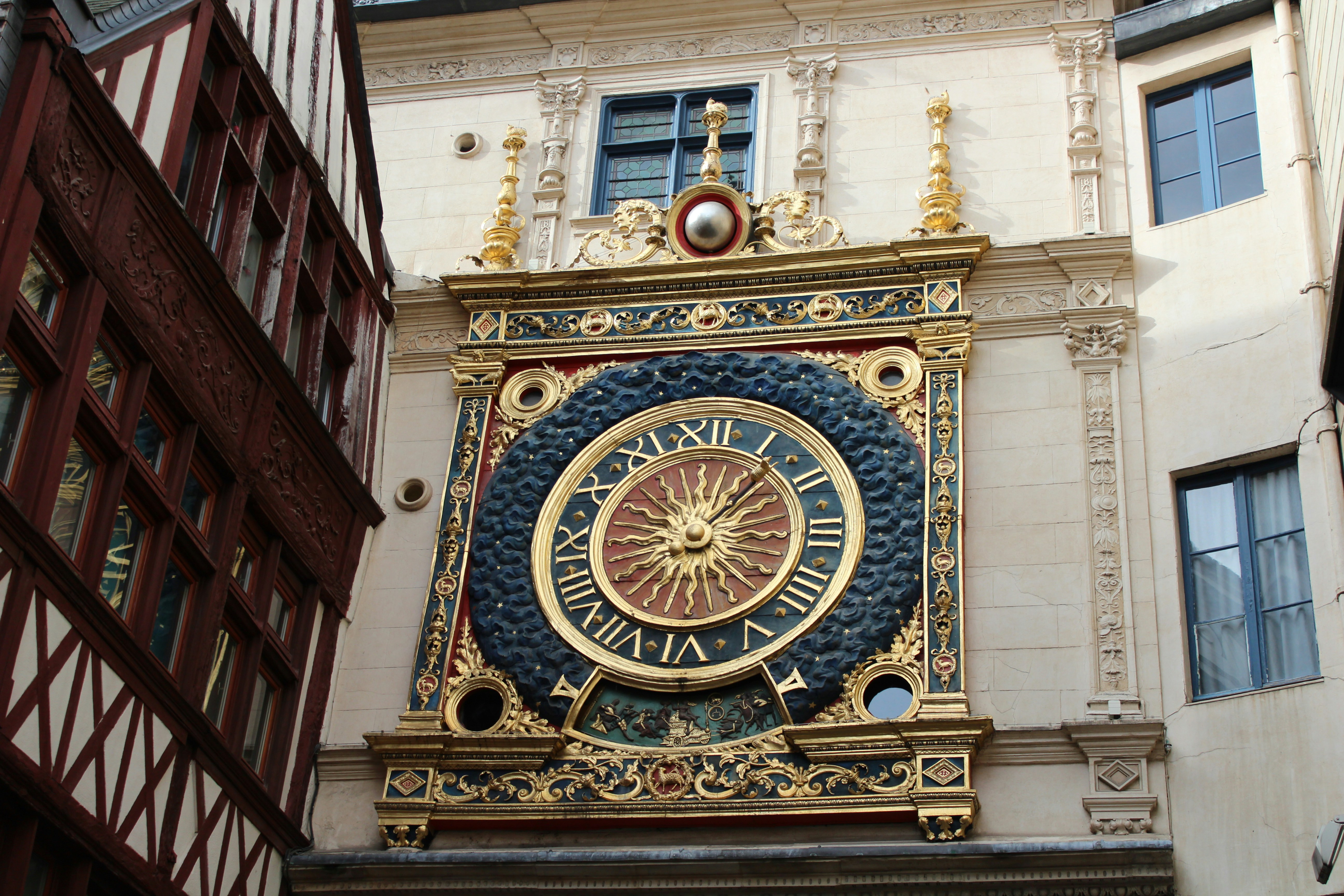 Sunburst Timekeeper: Gilded Clock on a Historic Facade