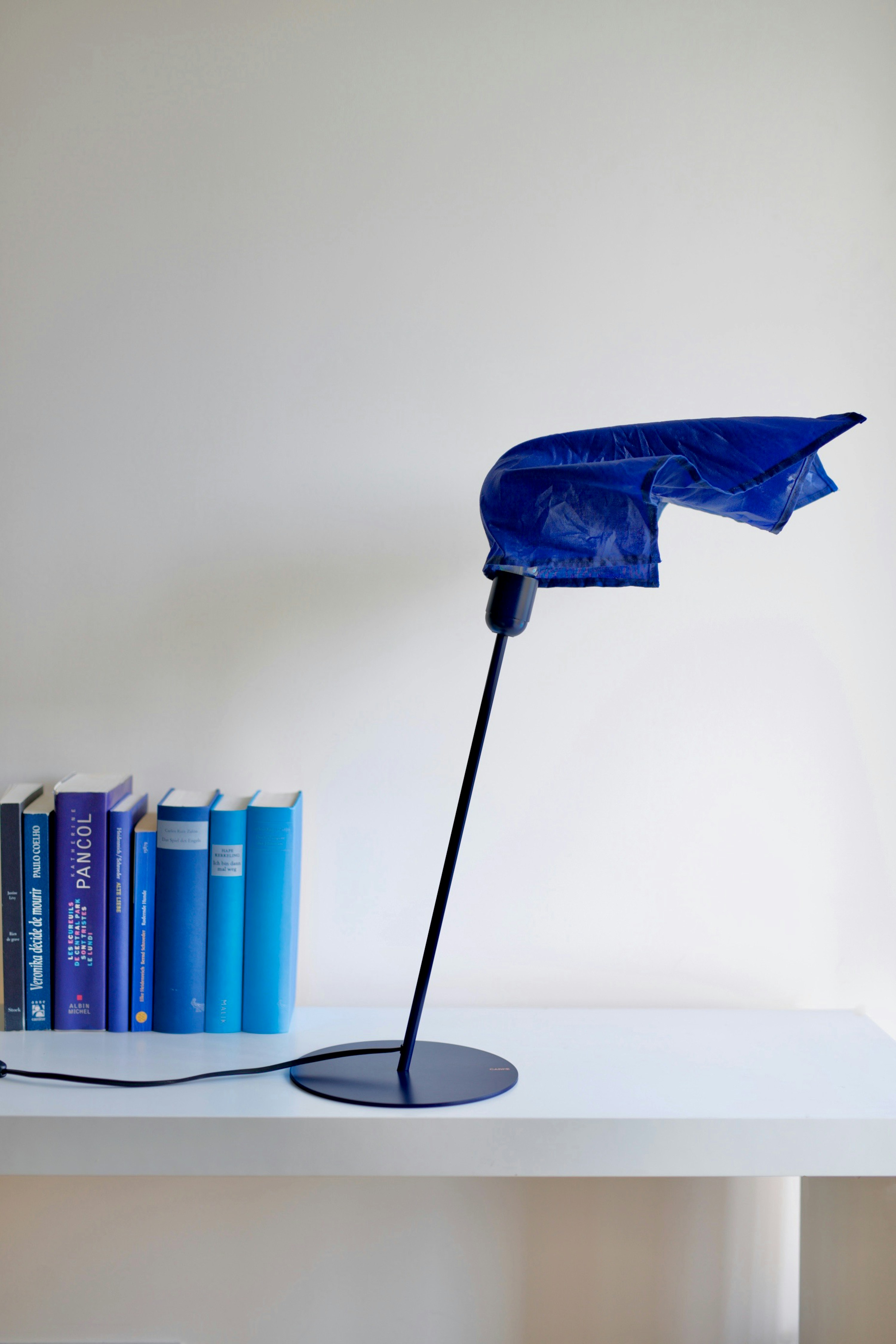 Cobalt shade lamp on a minimalist white desk forms a quiet study vignette