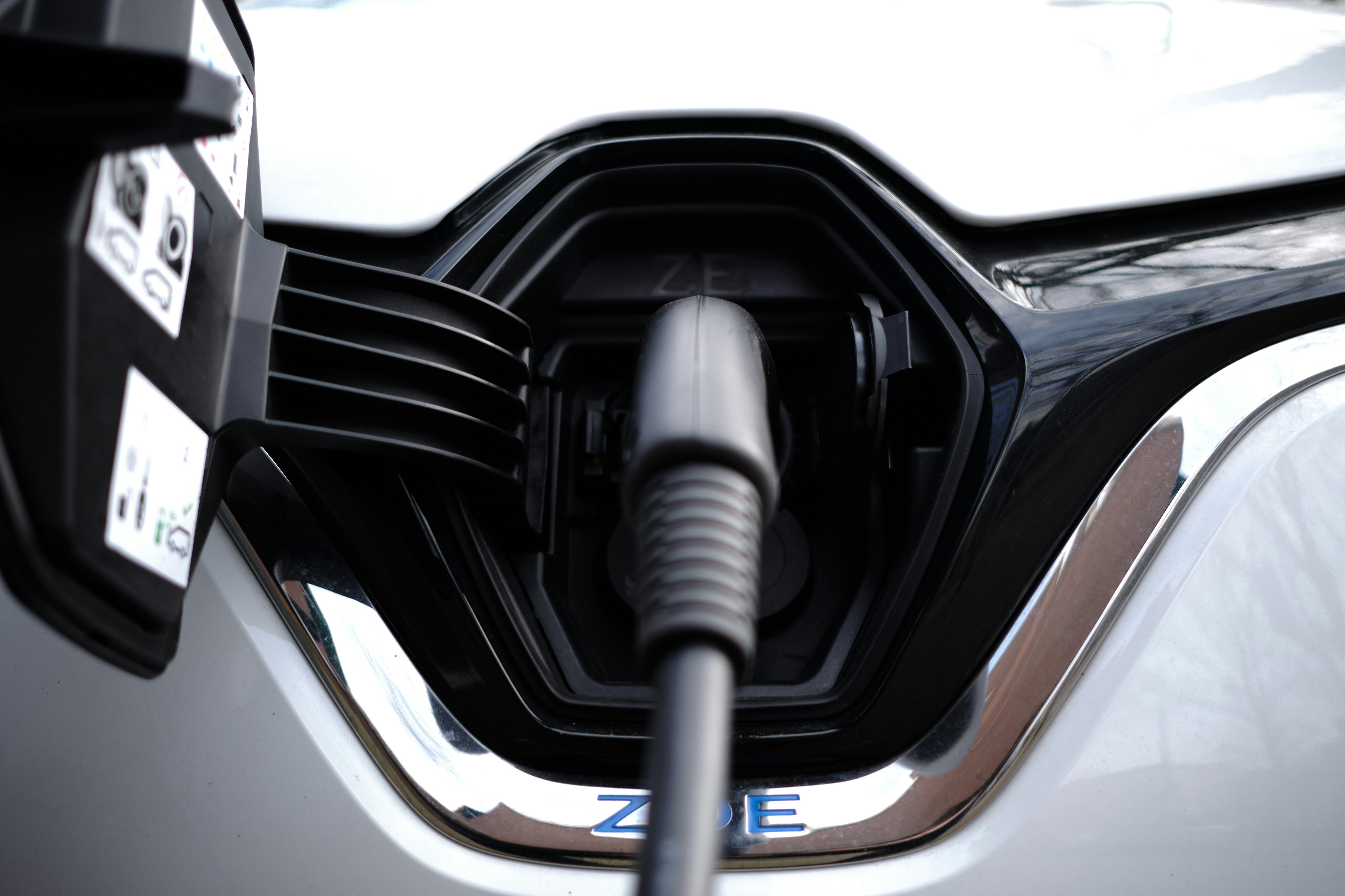 Close-up of an electric vehicle charging port with a cable connected, highlighting the modern design and technology behind electric vehicles.