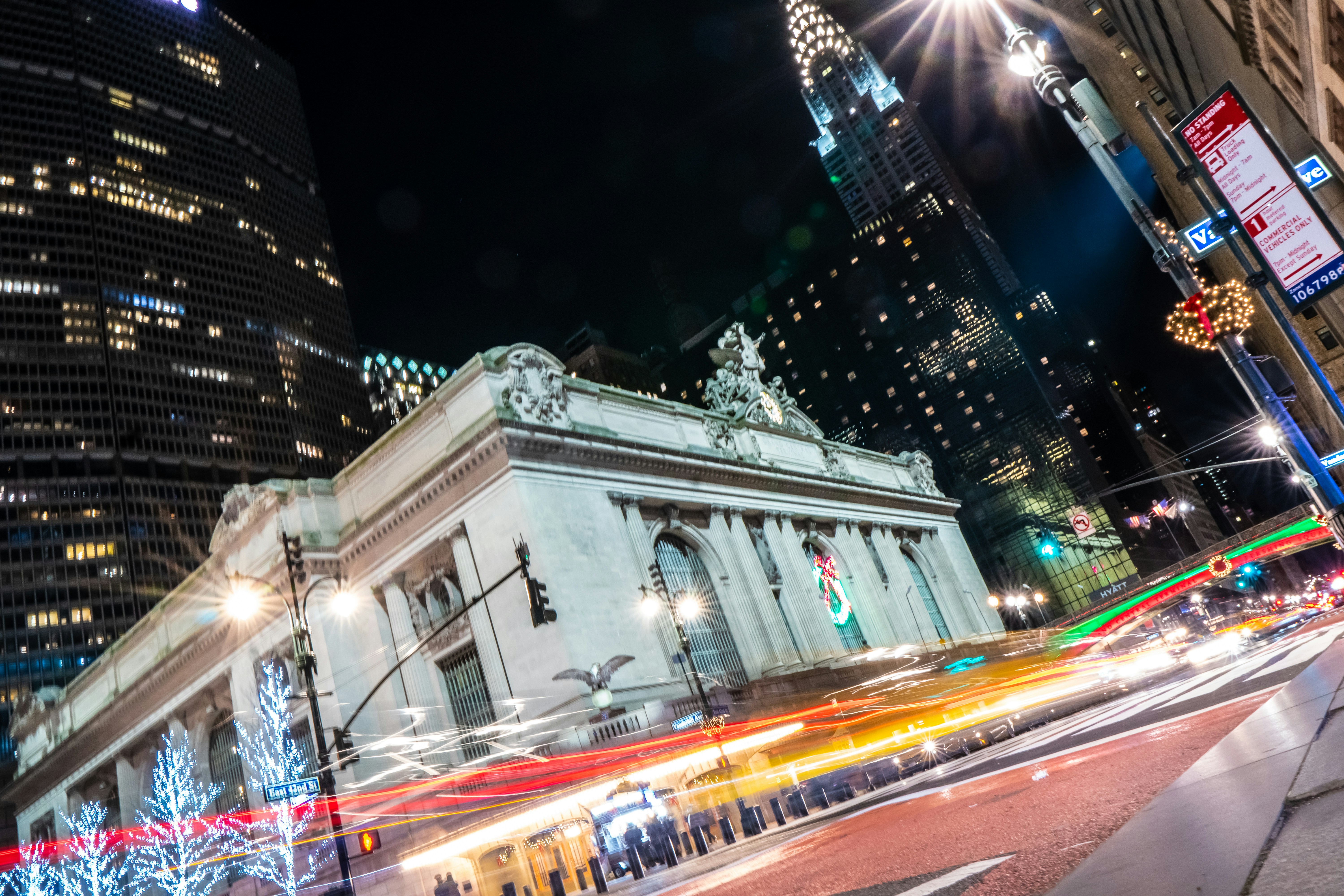Historic train station illuminated against a backdrop of skyscrapers, with streaks of car lights capturing the city's vibrant energy at night.