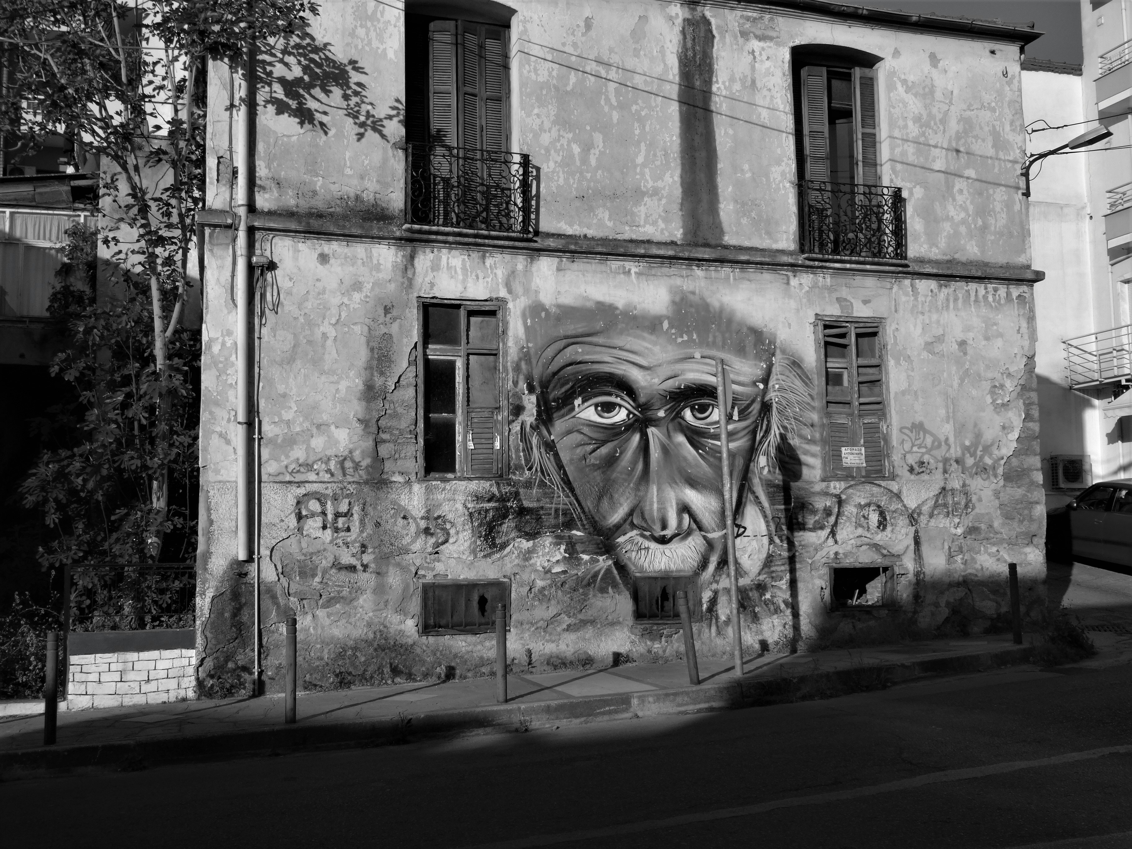 Gaze on the Wall: A Monochrome Graffiti Portrait Anchors a Quiet Street