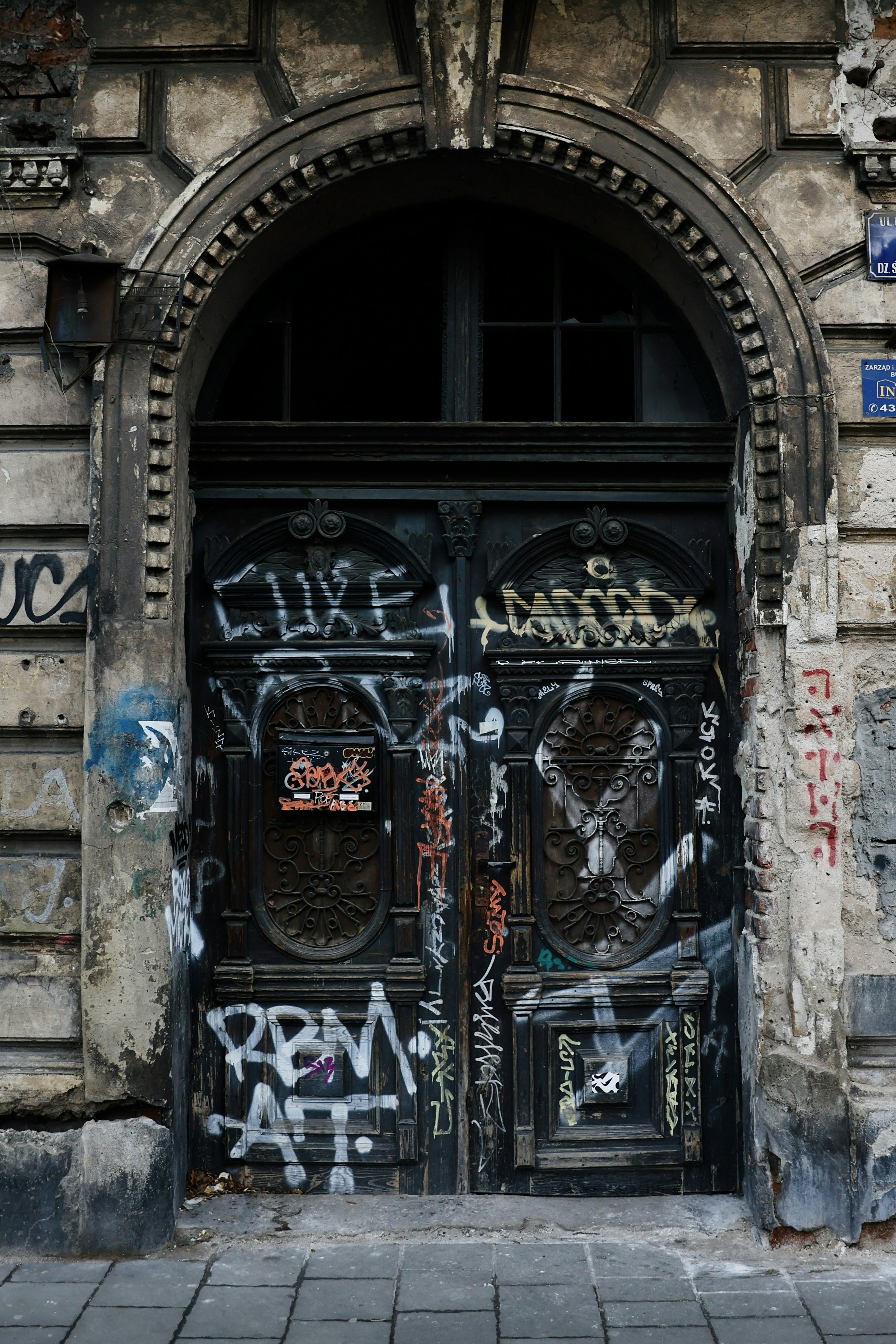 An intricately designed wooden door adorned with layers of graffiti, reflecting urban decay and history. The contrast between the craftsmanship and street art tells a compelling story.