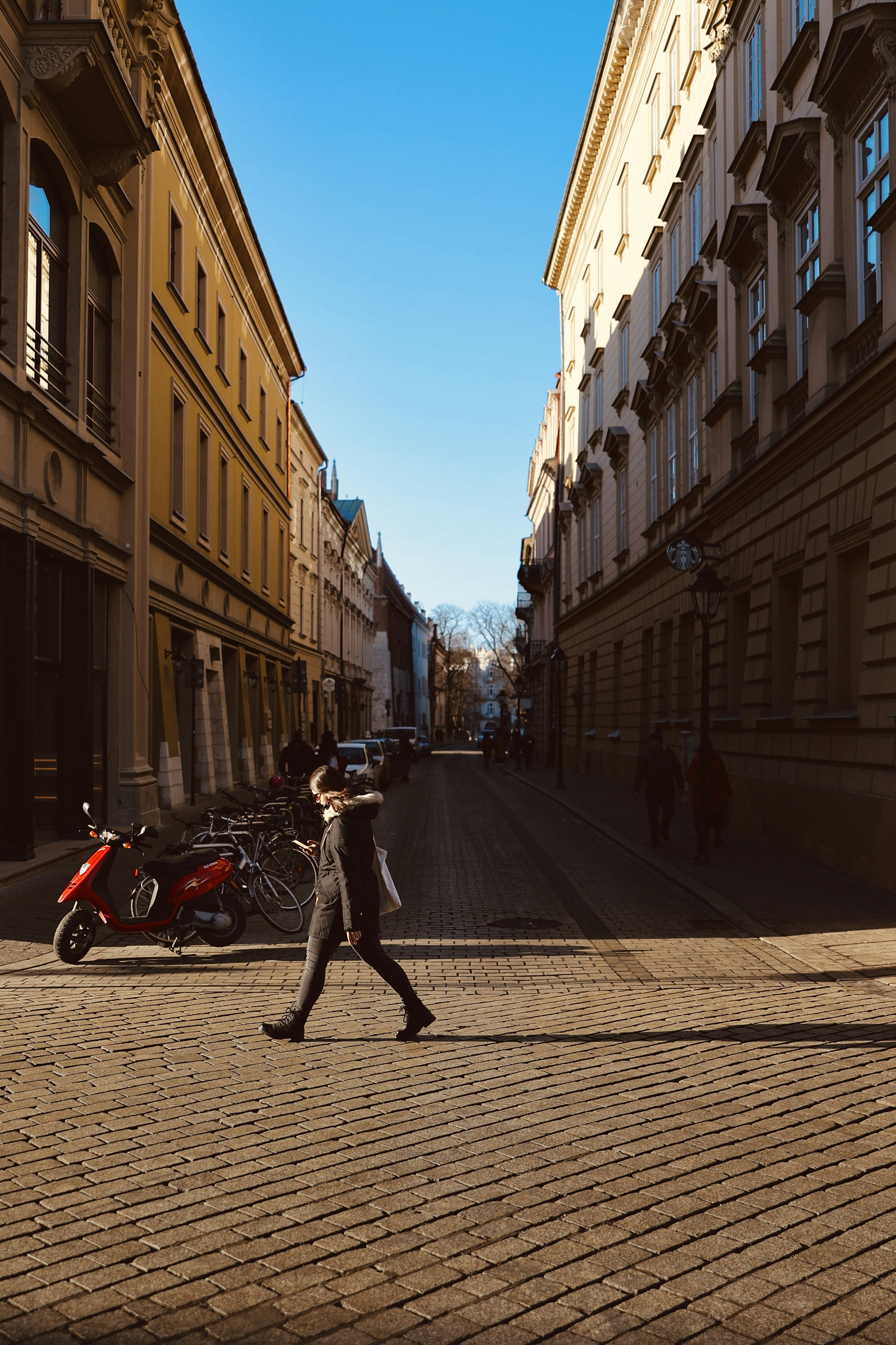 a man walking down a street next to tall buildings
