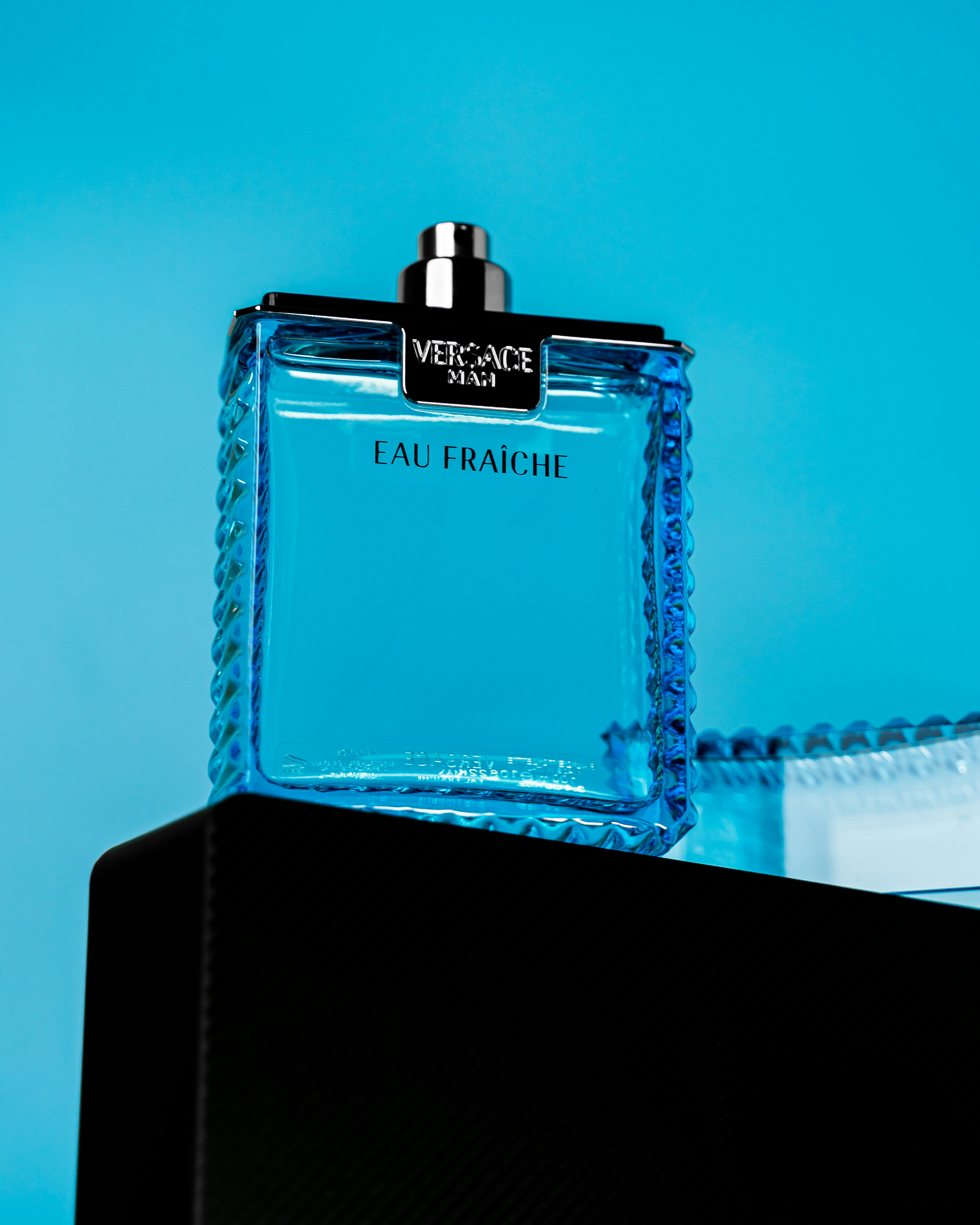 a bottle of perfume sitting on top of a black box
