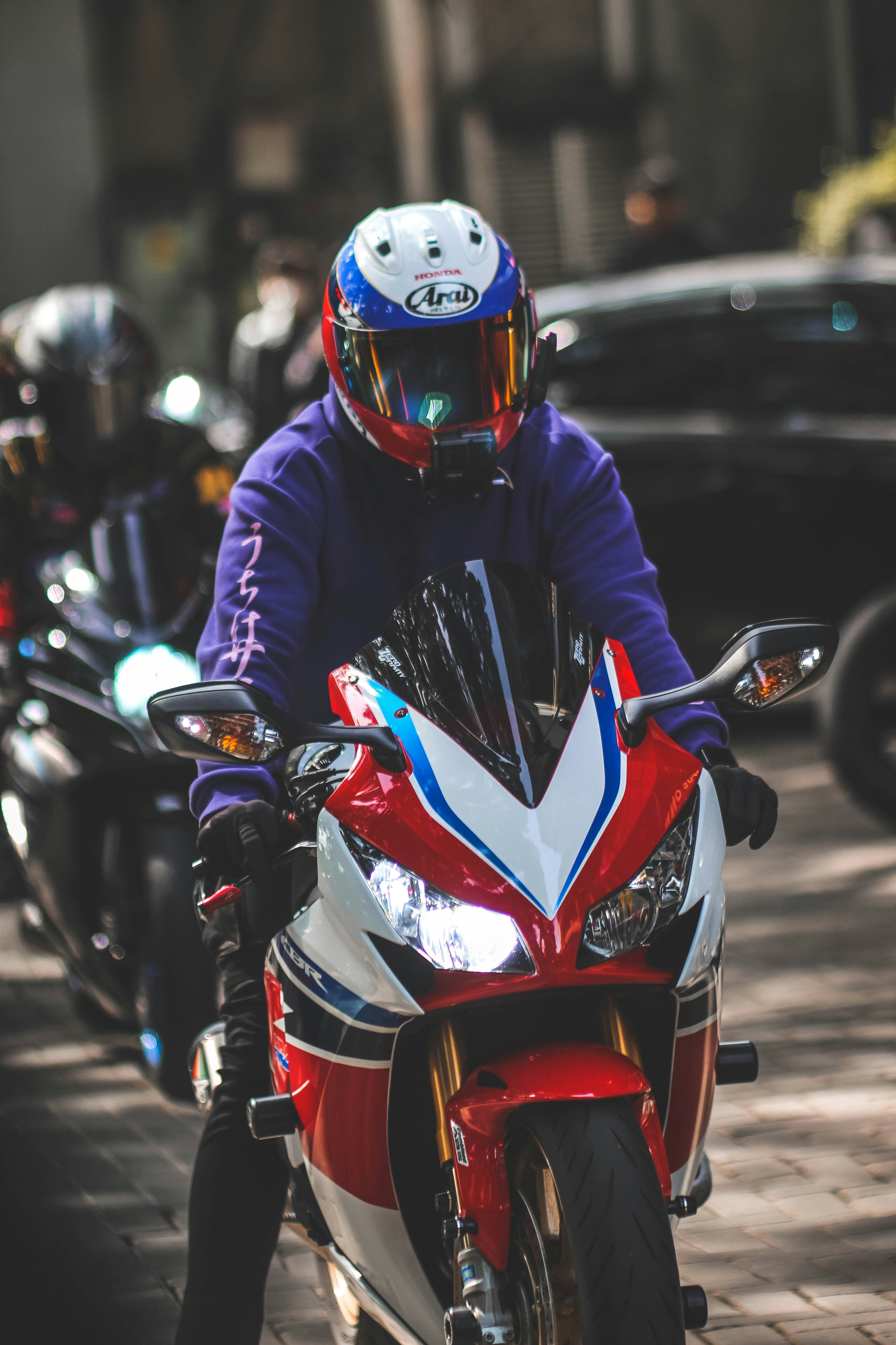 A person riding a motorcycle on a city street photo – Free Clothing ...