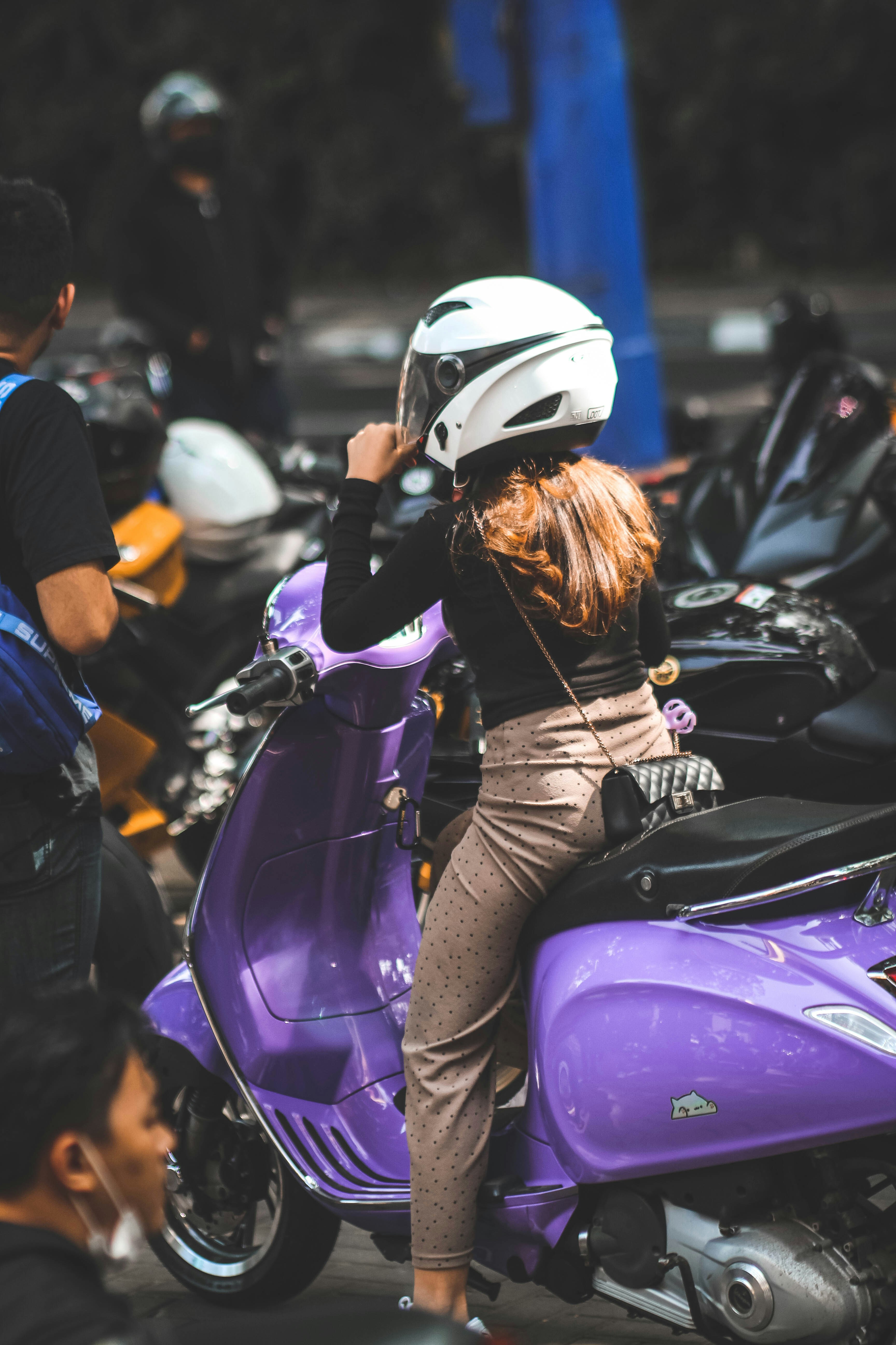 A woman riding a purple scooter with a helmet on photo – Free Apparel ...