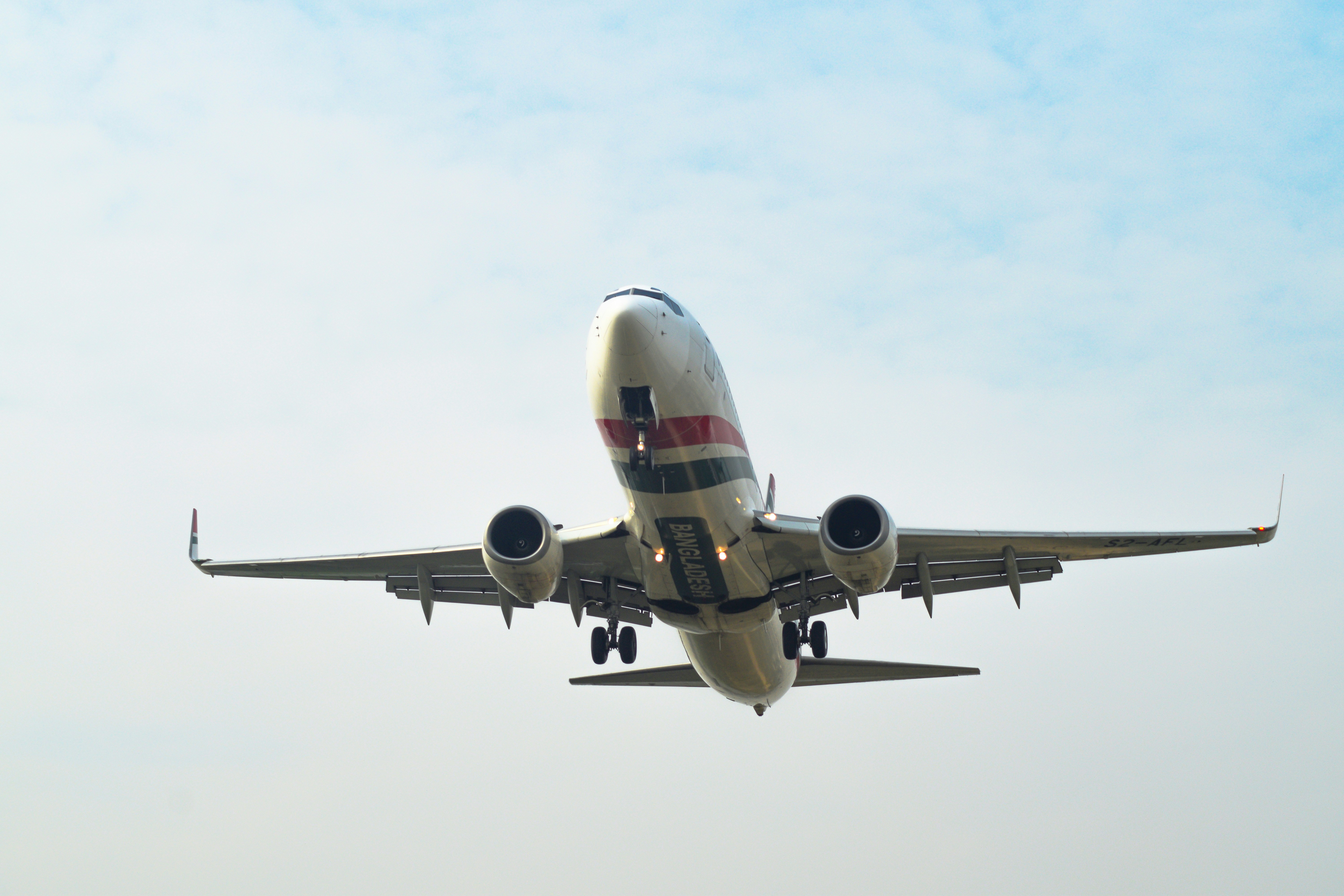 Large jetliner soaring through a clear blue sky, viewed from below.