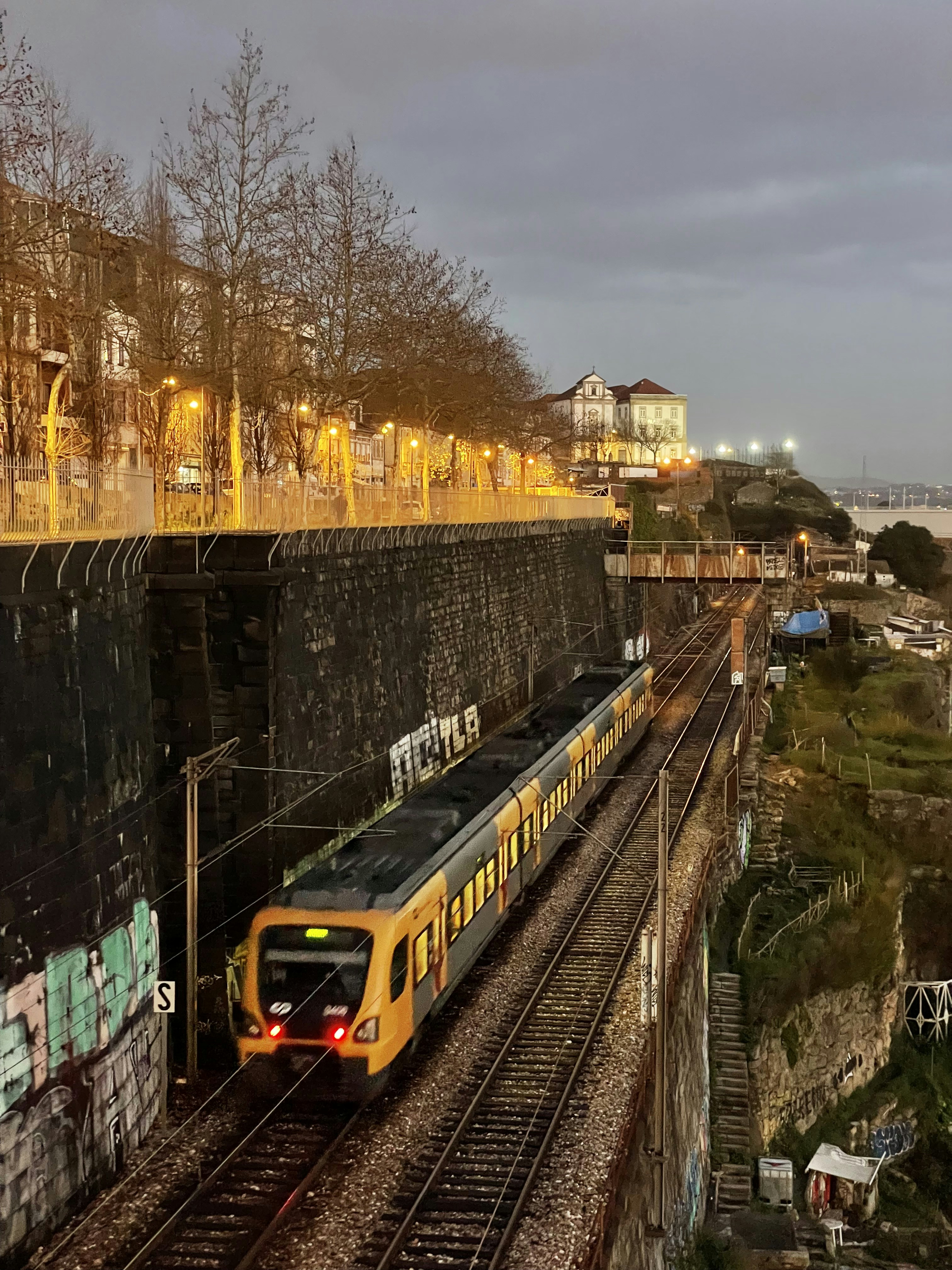 a yellow train traveling down train tracks next to a forest