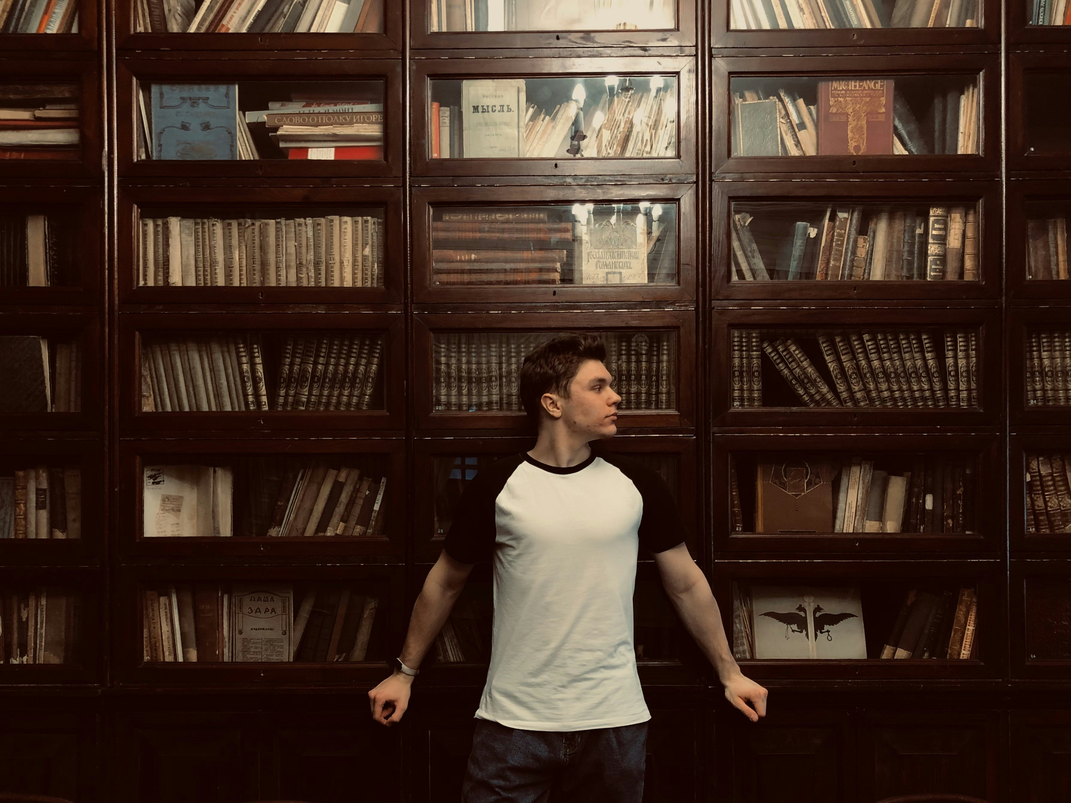A man standing in front of a bookshelf full of books photo – Free Human ...