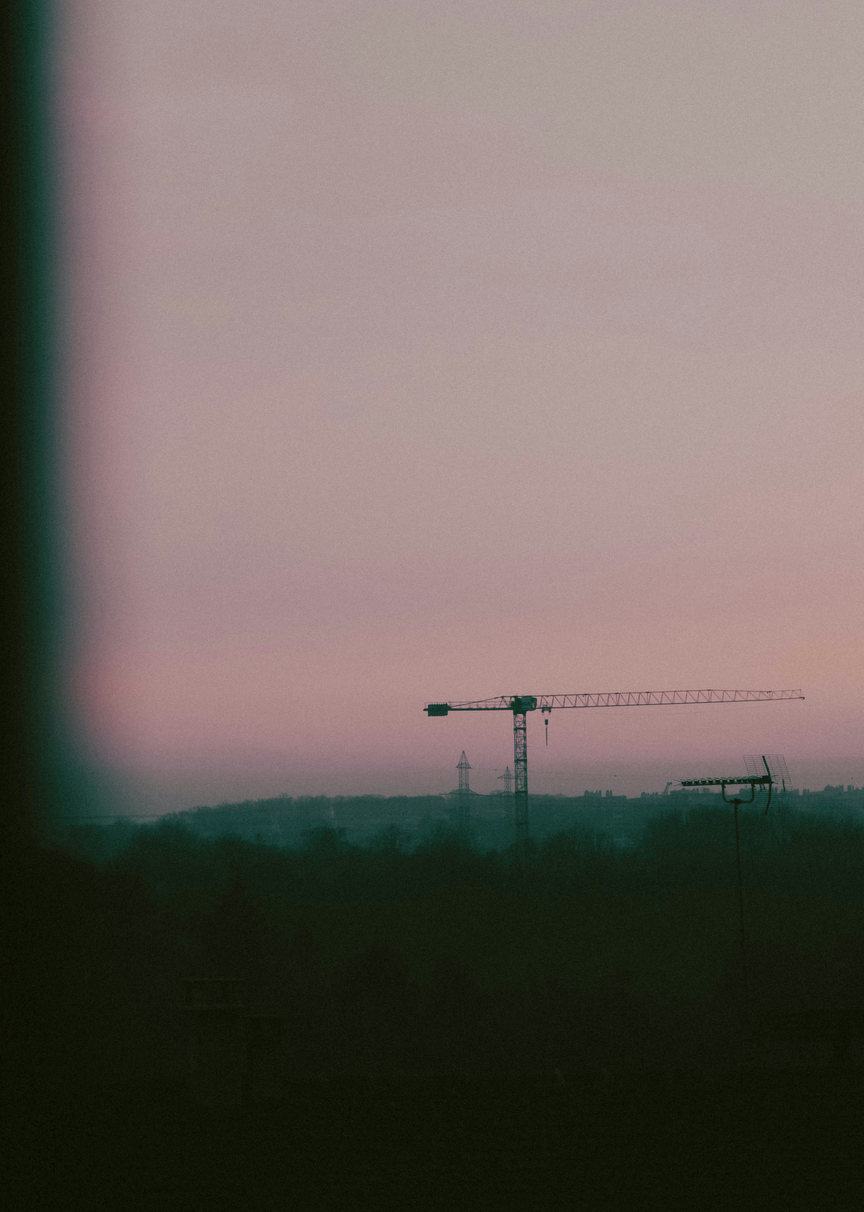 Silhouetted construction crane against a pastel sky, hinting at urban development and change.