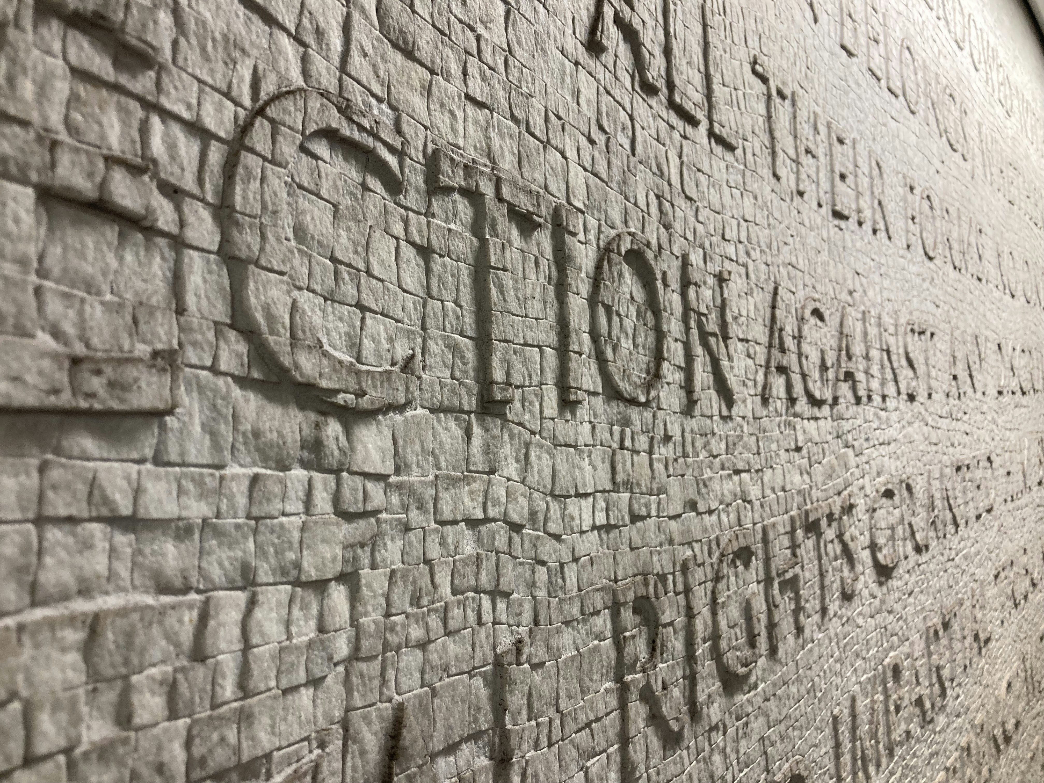 Stone Script in Perspective: Carved Letters Recede Across a Textured Wall