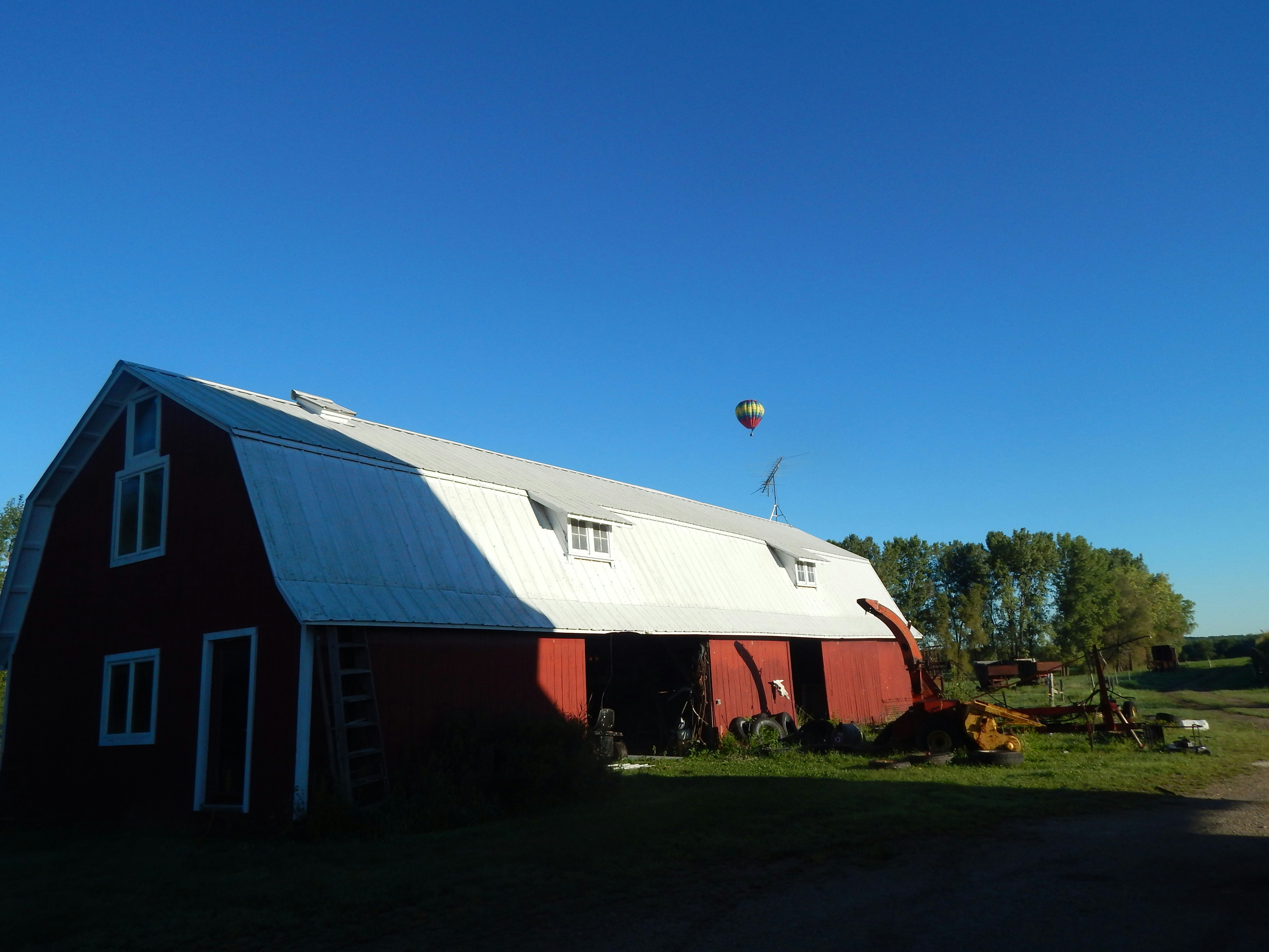 A red barn with a hot air balloon in the sky photo – Free Summer Image ...