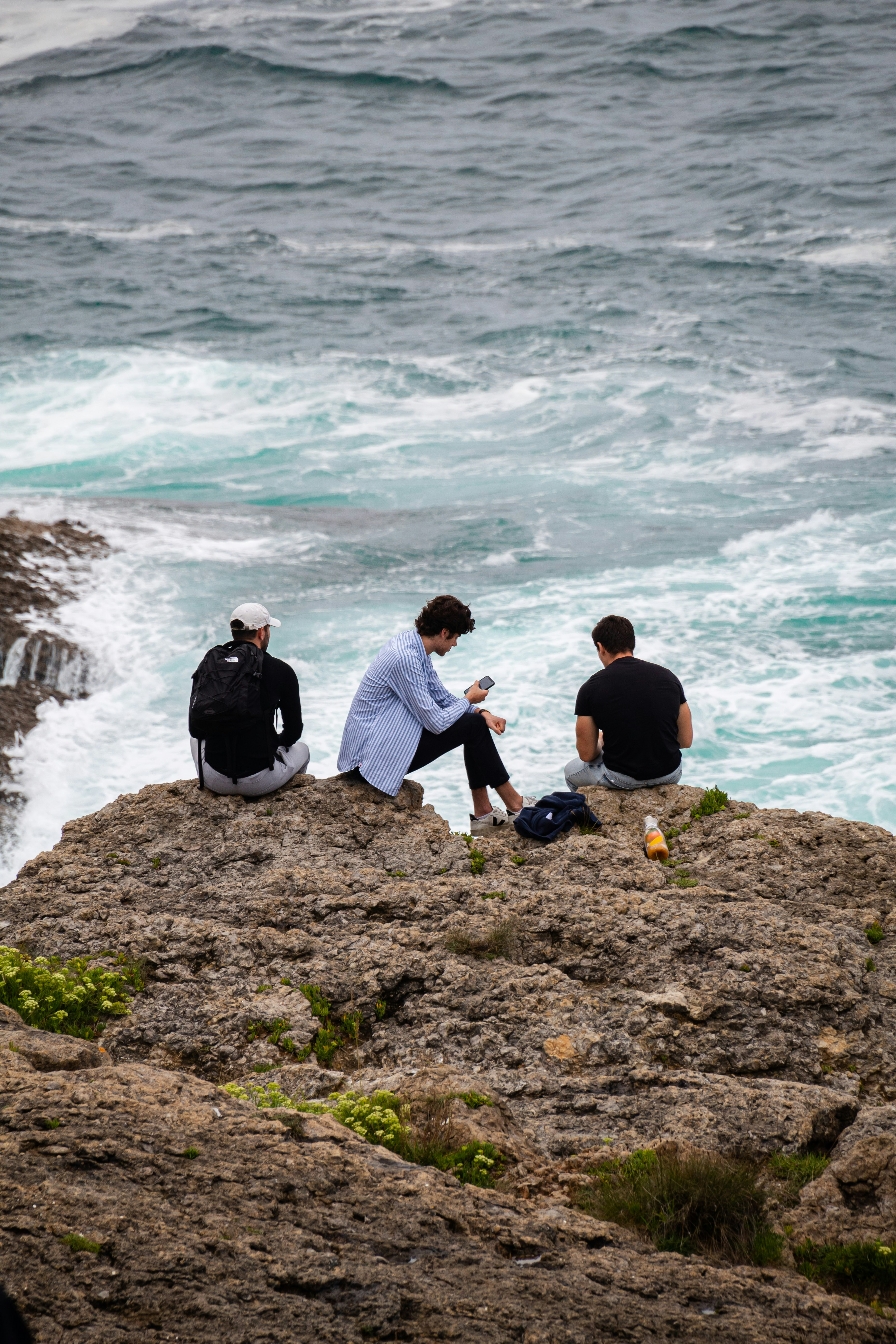 Three Friends on a Wind-Worn Cliff Over Turquoise Breakers