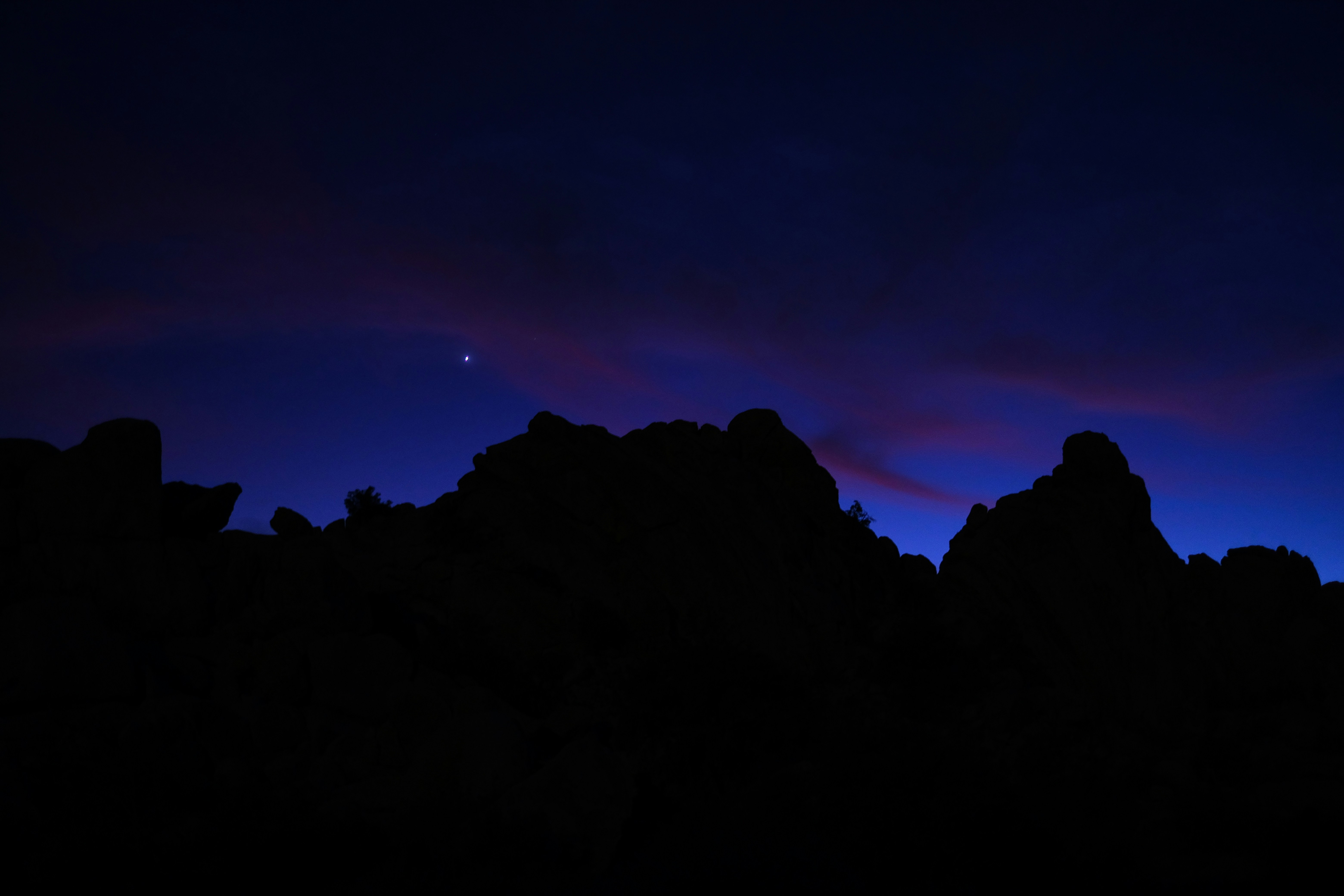 the sky is dark and blue with a few clouds