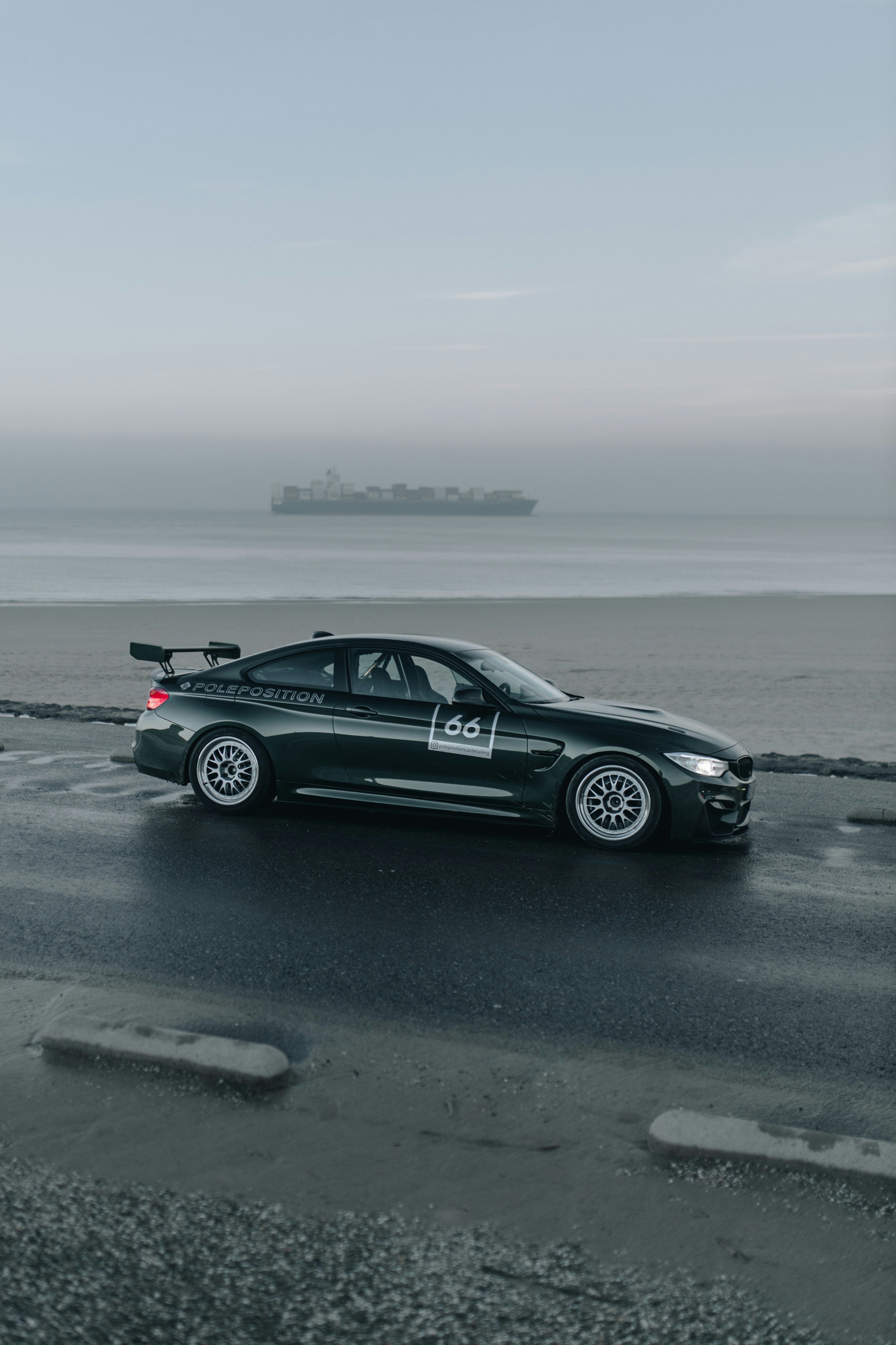 Green race car by the shoreline under a foggy horizon