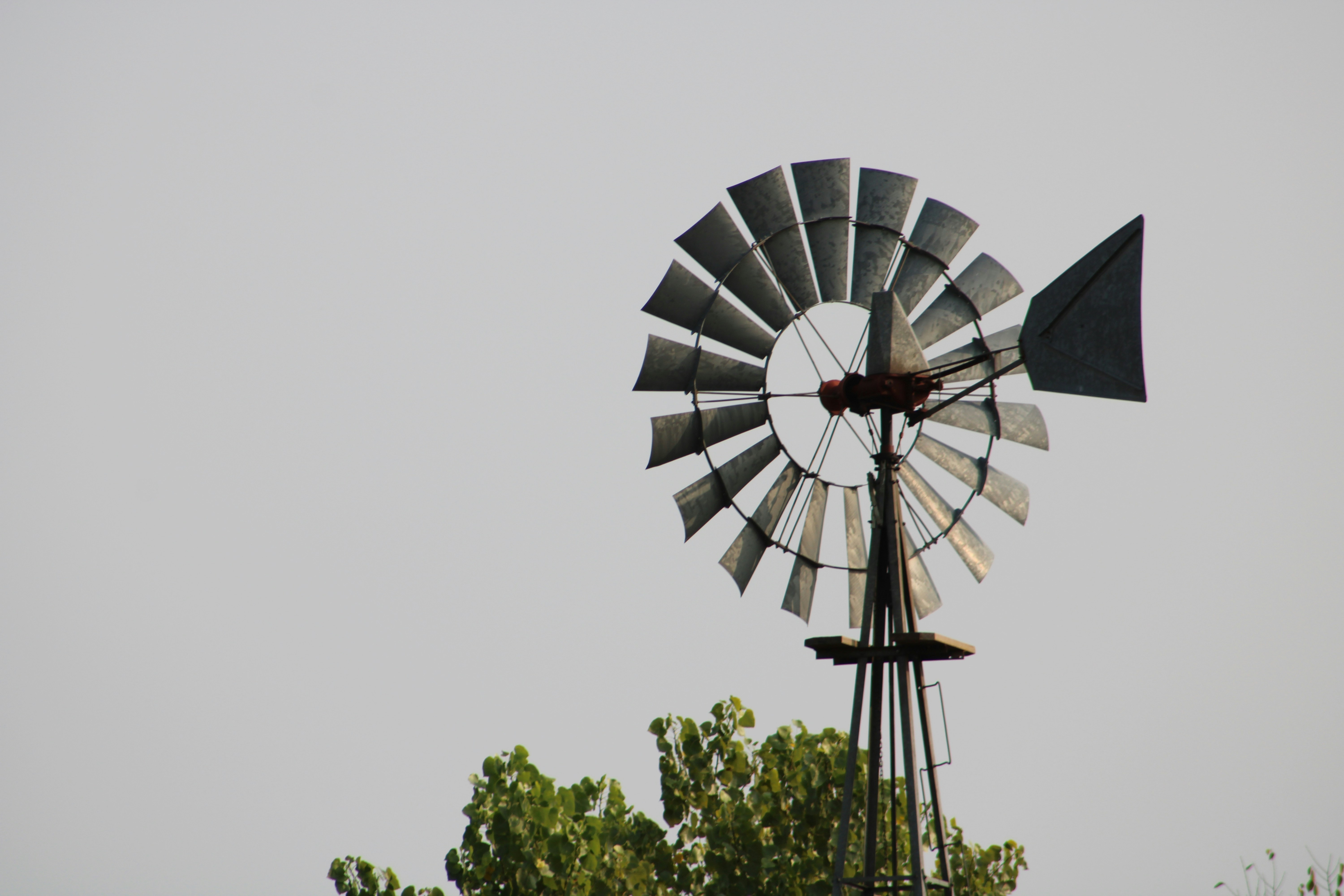 a windmill sitting next to a tree on a cloudy day