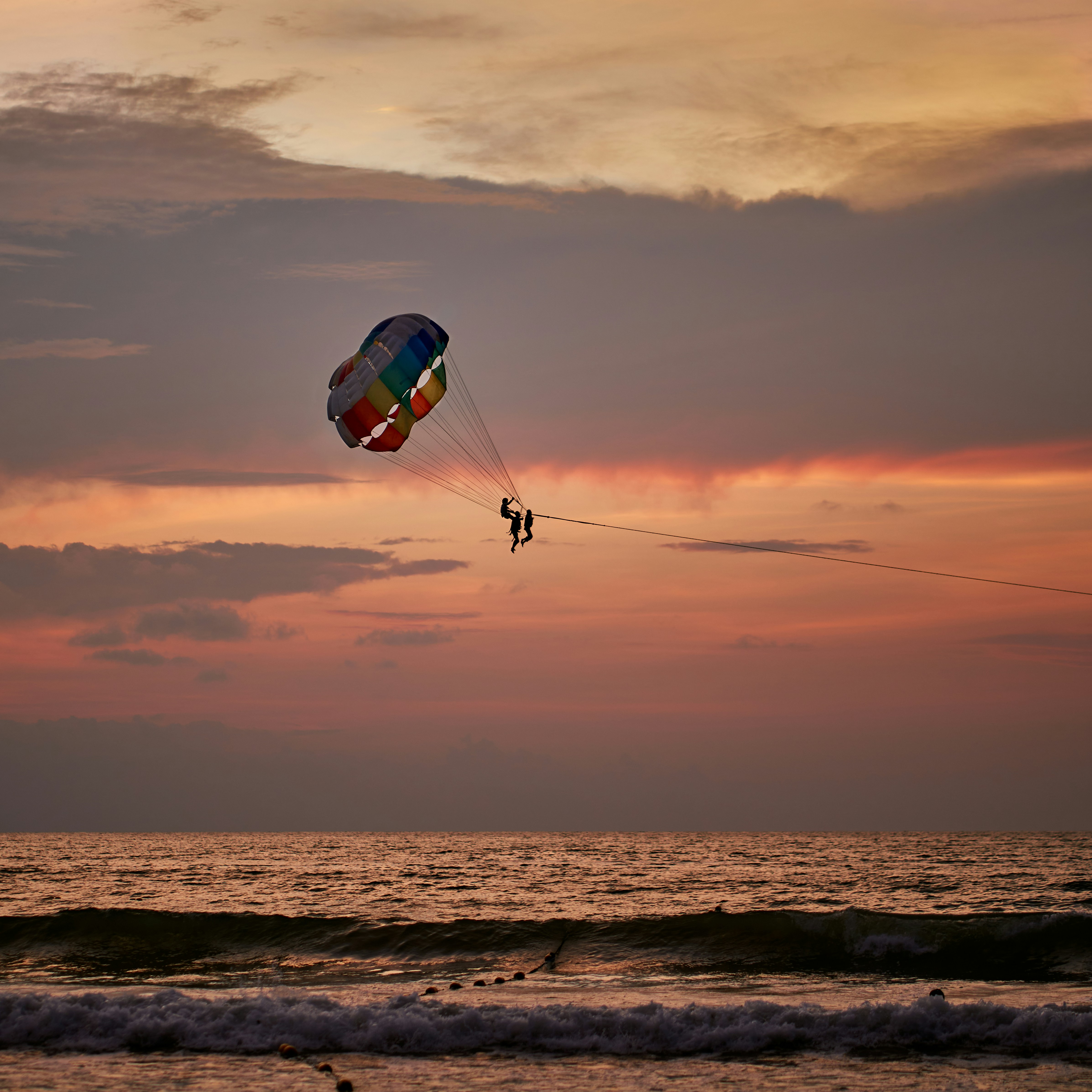 Une personne fait du parachute ascensionnel dans l’océan au coucher du ...