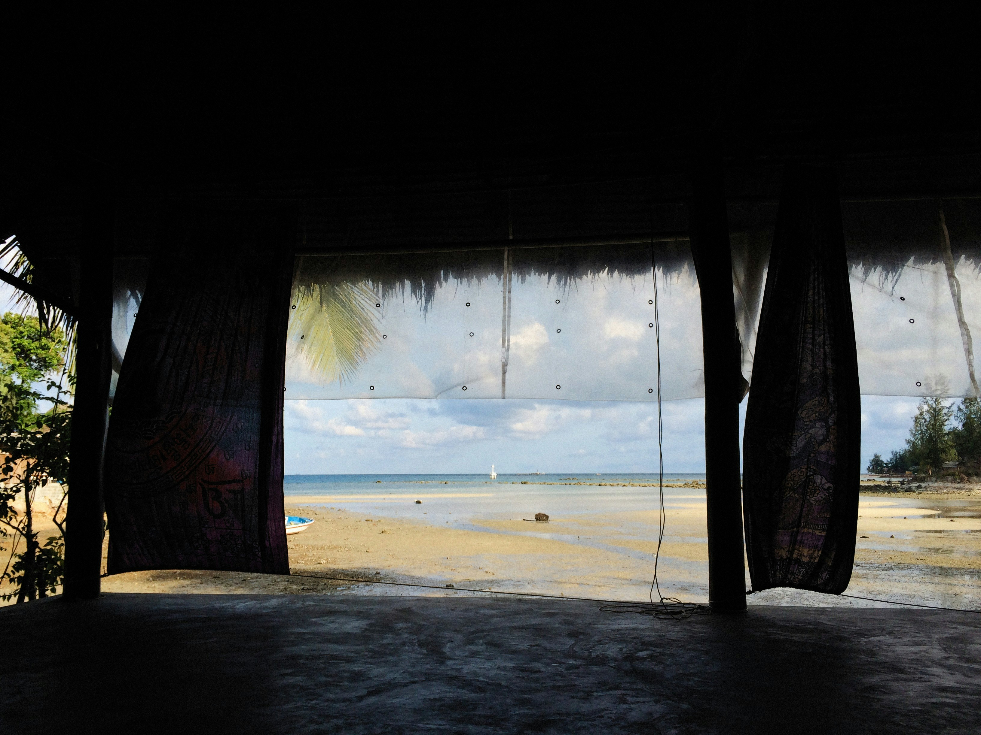 a view of a beach from inside a hut